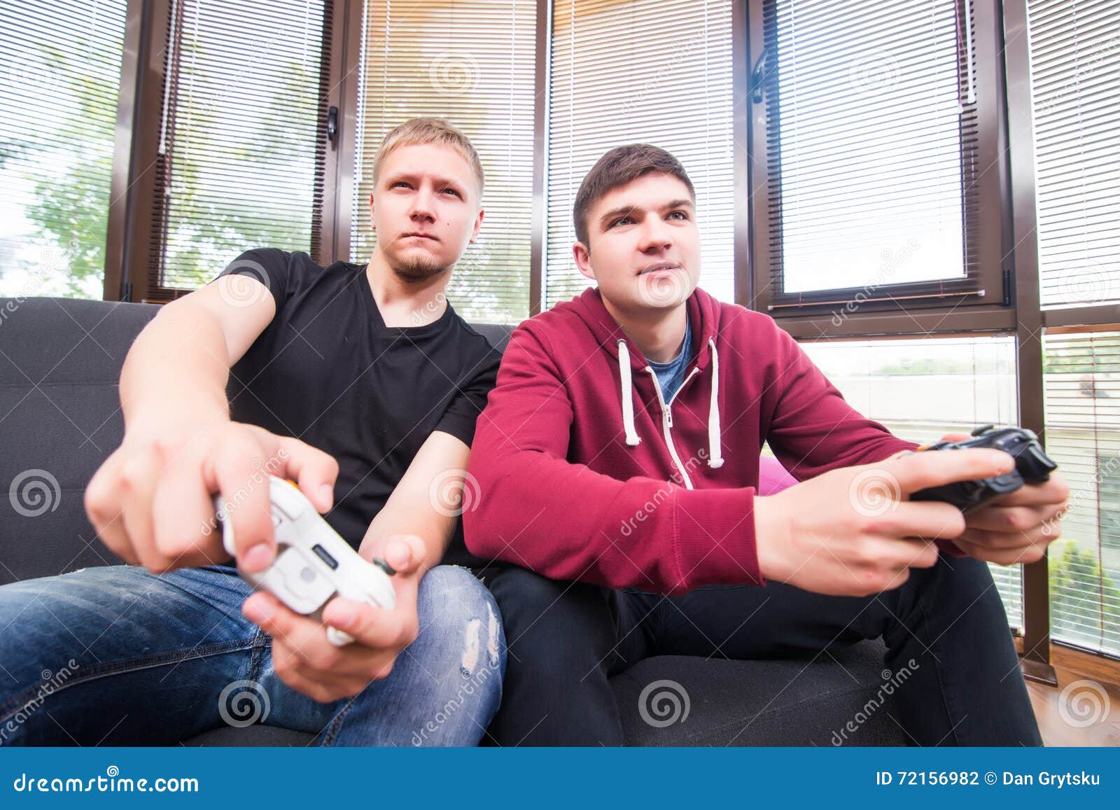 Two Handsome Young Men Playing Video Games while Sitting on Sofa Stock ...
