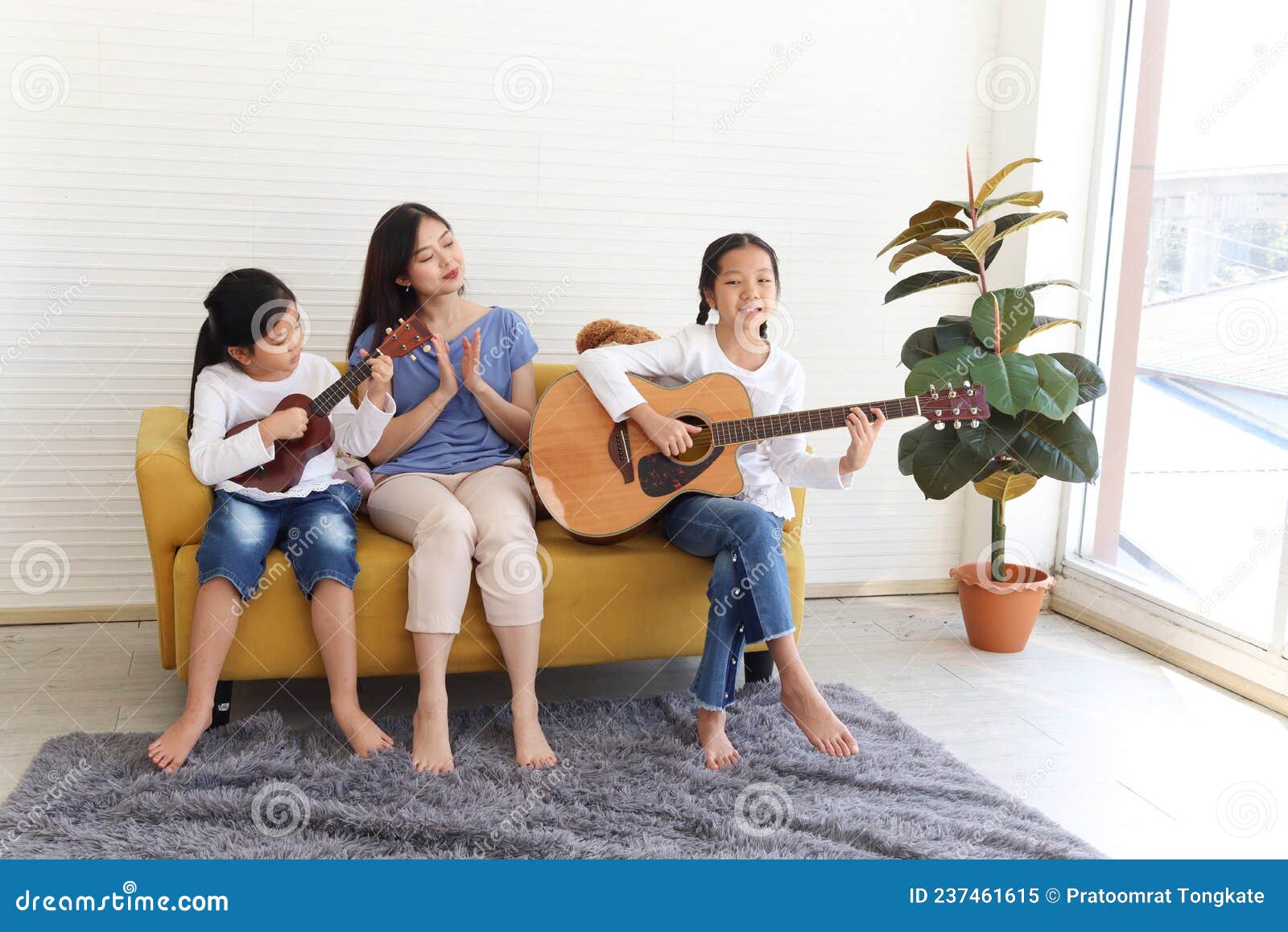 Two Happy Daughter Girls And Mother Singing A Song And Playing Guitar