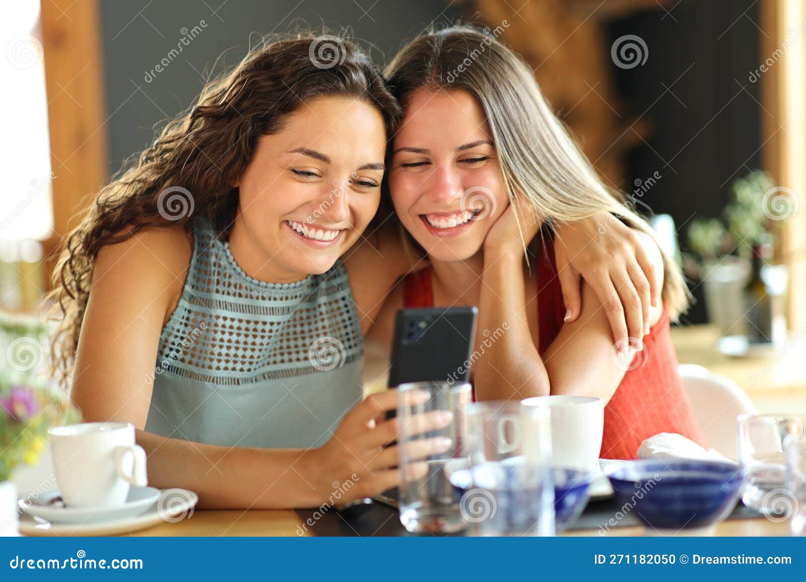 Two Happy Friends Checking Cell Phone Content in a Restaurant Stock ...
