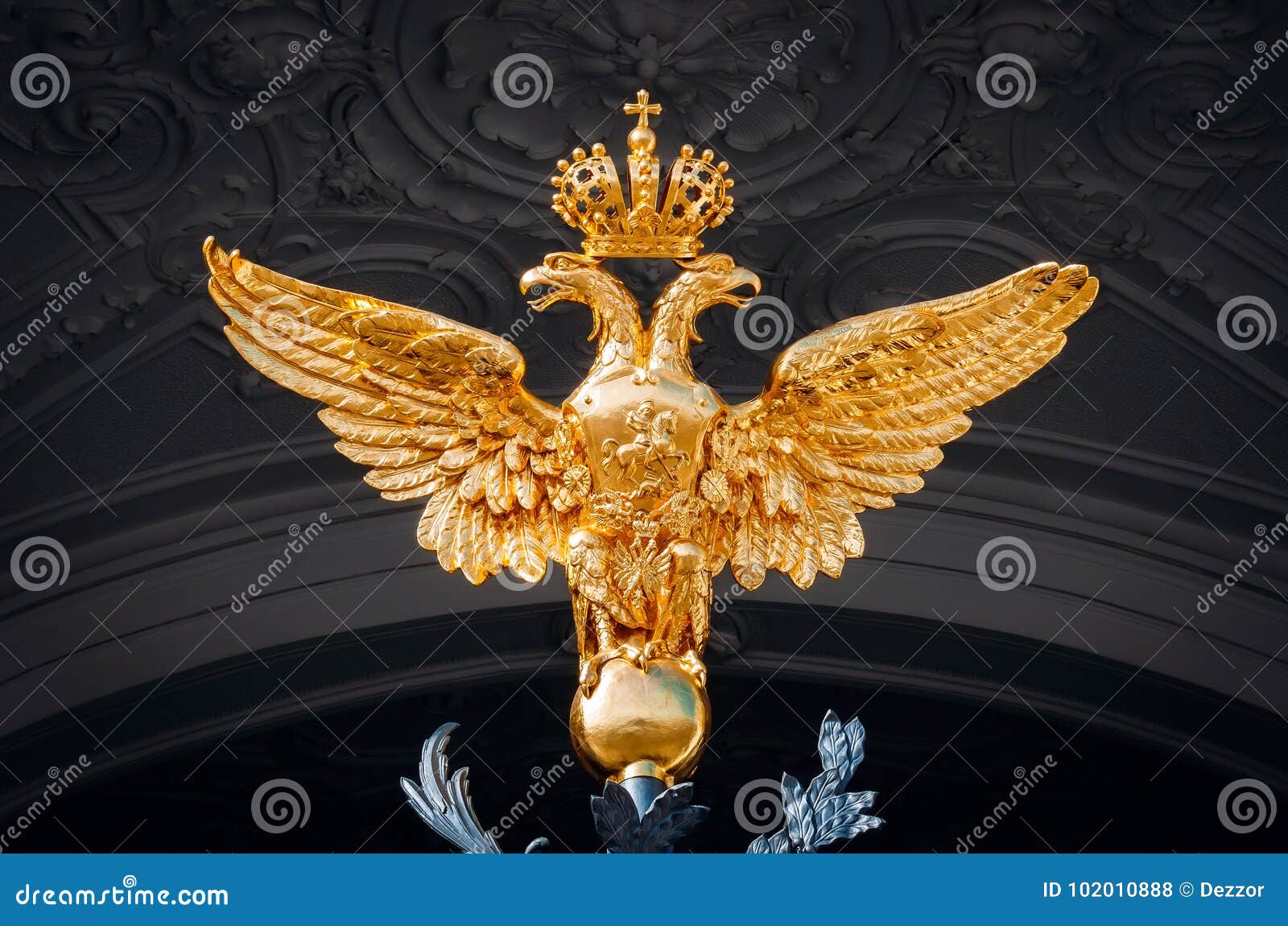 Two-headed Golden Eagle On The Background Of The Blue Sky-a Spire On ...