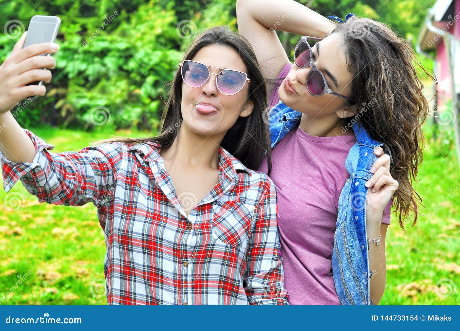 Two Joyful Fanny Pretty Girls Having Fun Taking A Selfie On Mobile