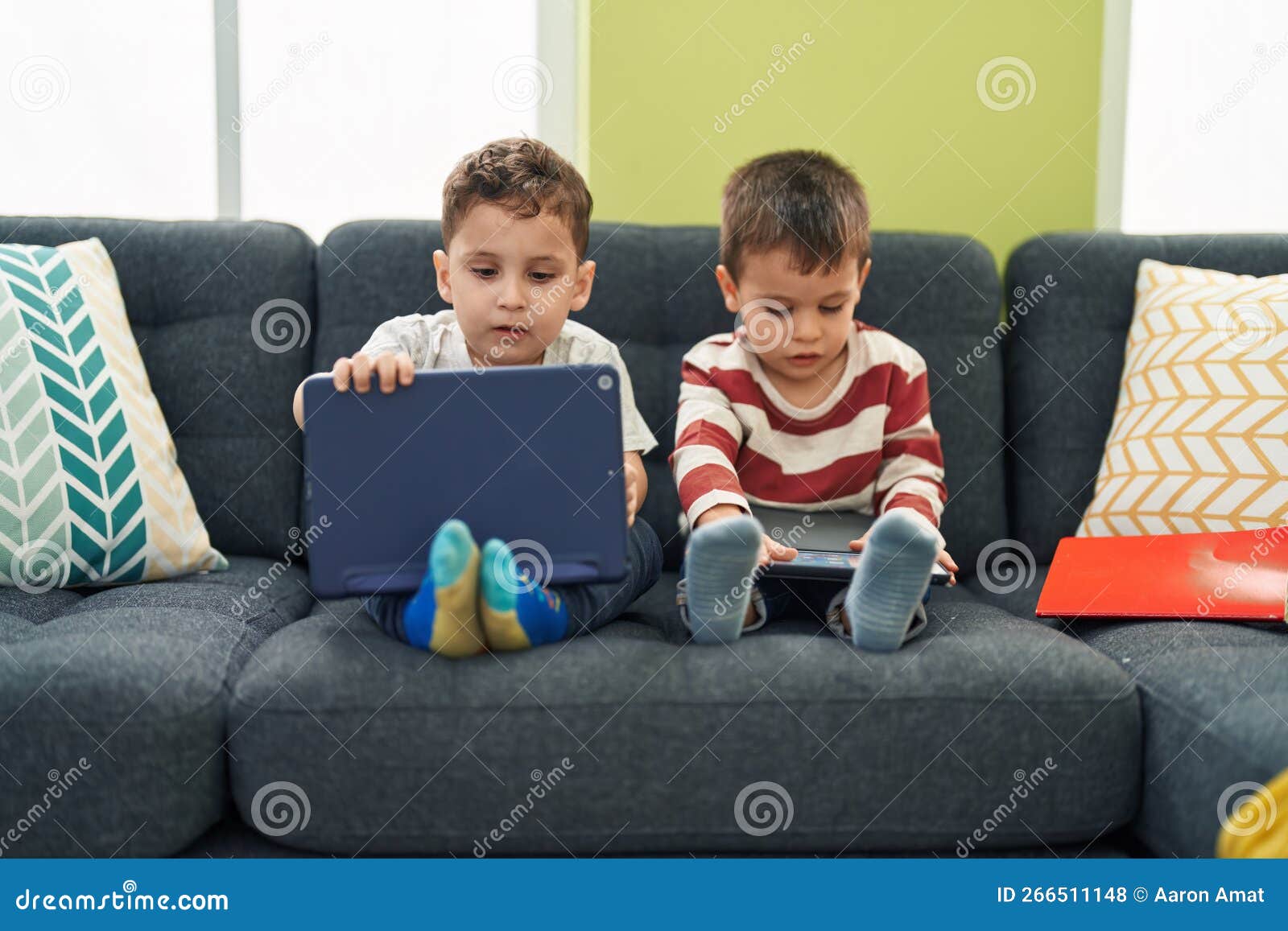Two Kids Watching Video on Touchpad Sitting on Sofa at Home Stock Photo ...
