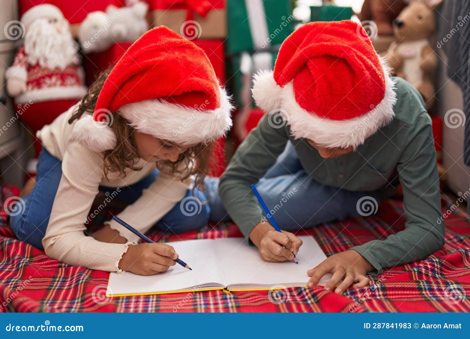 Two Kids Writing on Notebook Sitting on Floor by Christmas Tree at Home ...