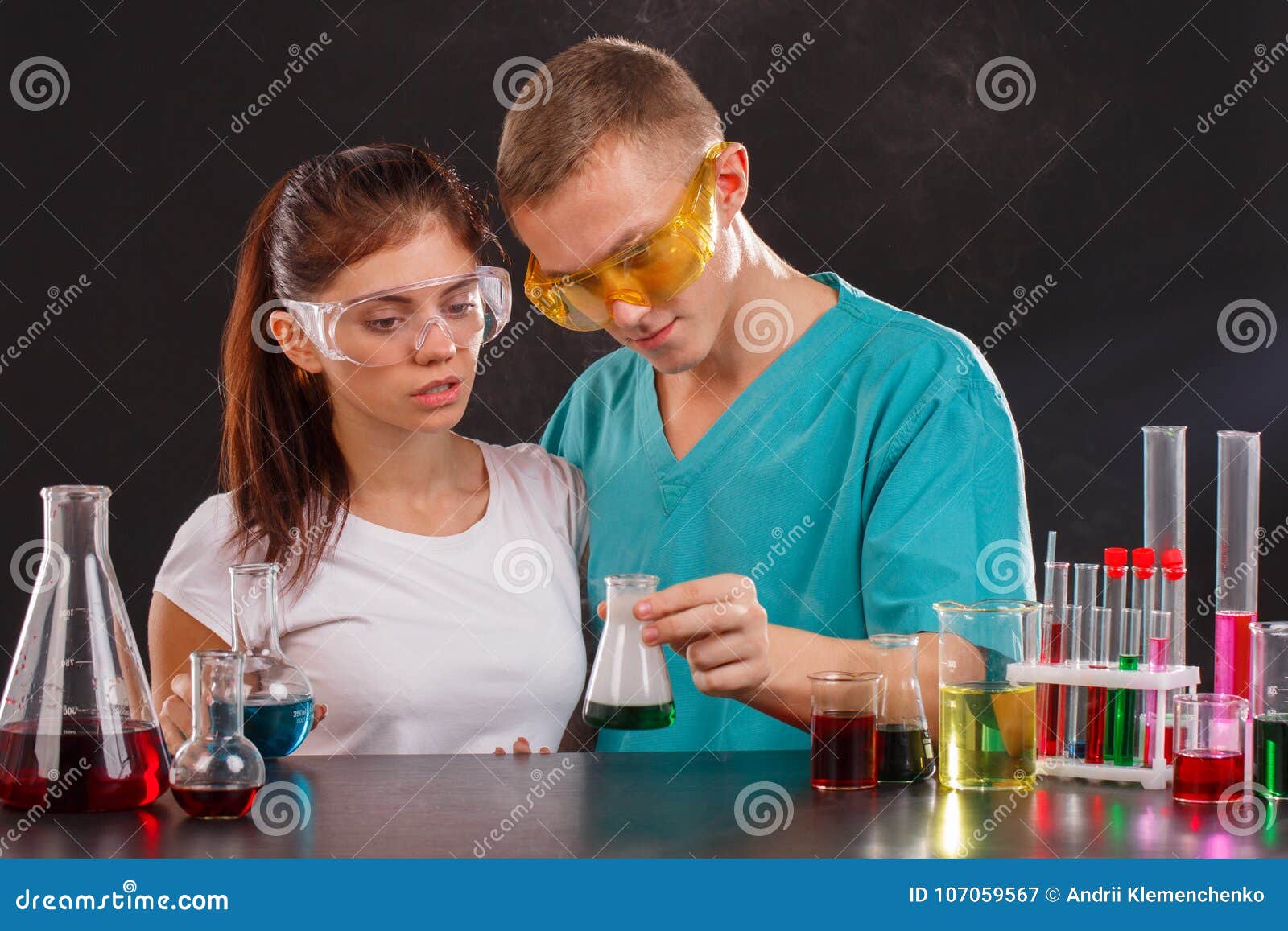 Two Lab Technicians are Examining a Flask with a Green Liquid that the ...