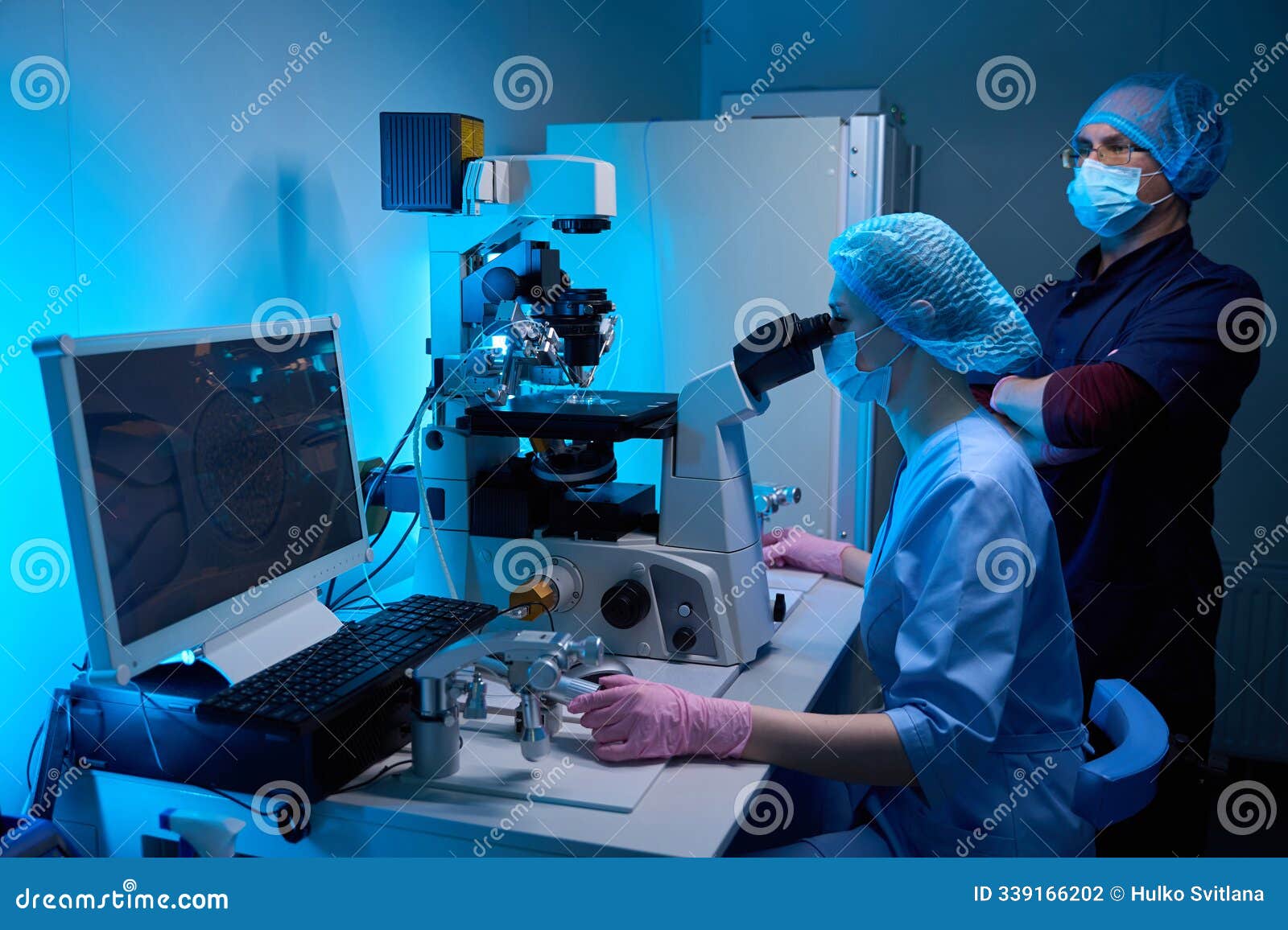 Two Lab Technicians Working with a Microscope and Computer in a ...