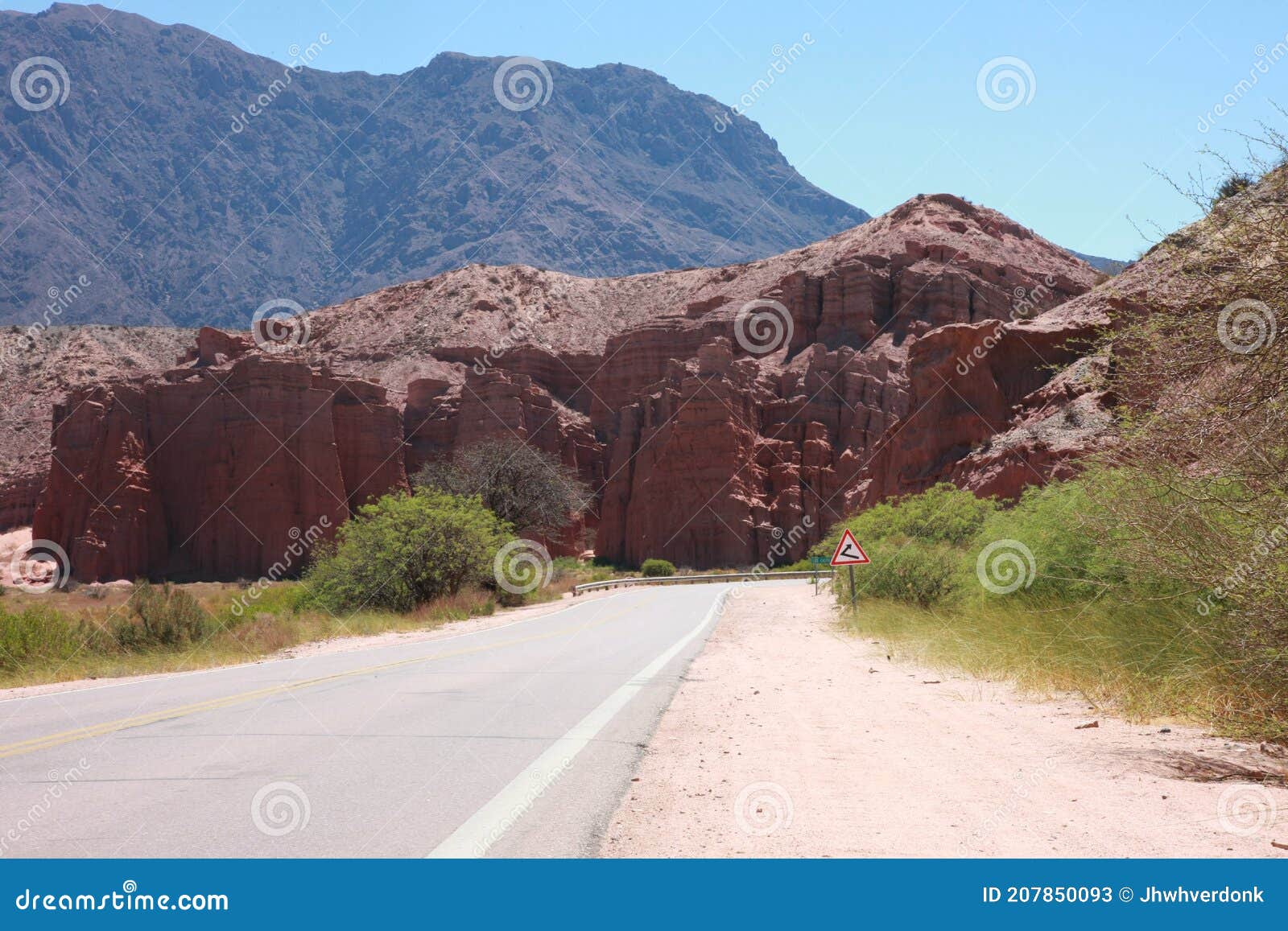A Two Lane Road Running Down a Slight Slope through the Mountains of ...