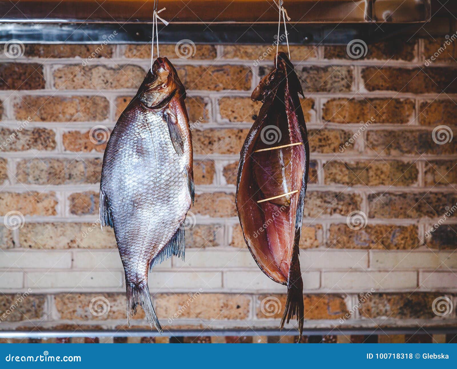 Two Large Smoked Fish Hanging on Brick Wall Background Stock Photo ...