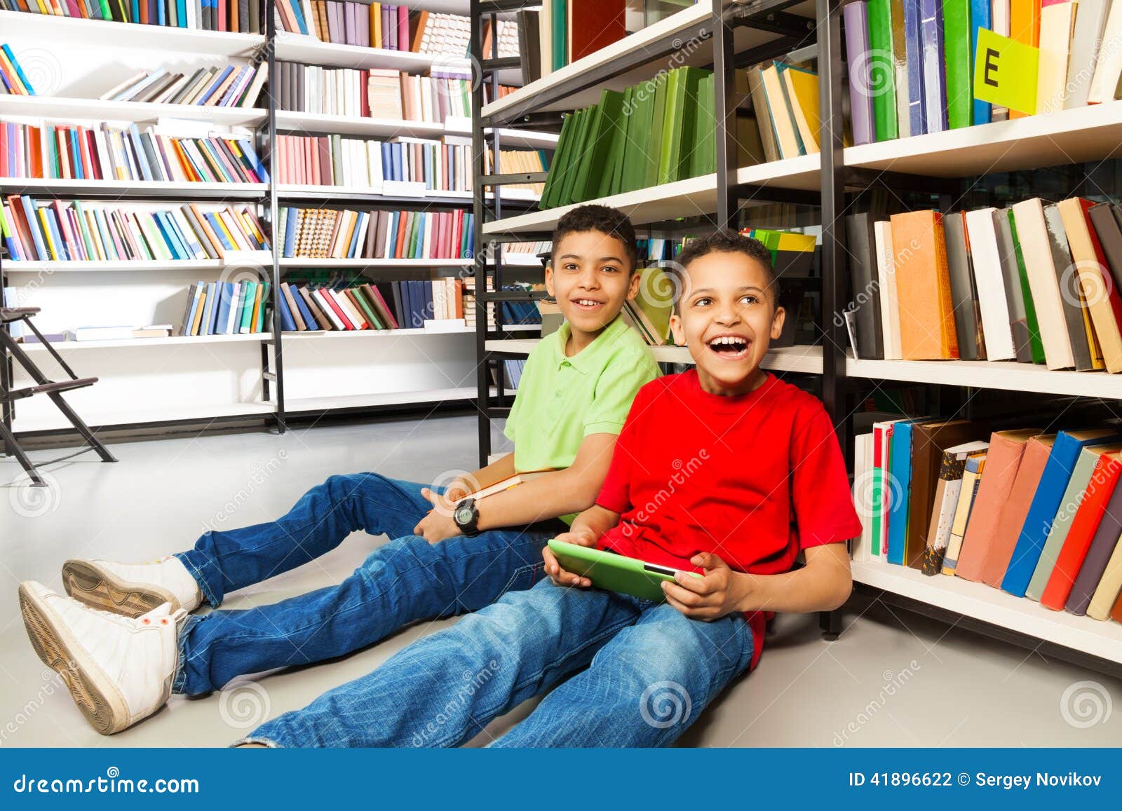 Two Laughing Boys Sitting on the Floor in Library Stock Photo - Image ...