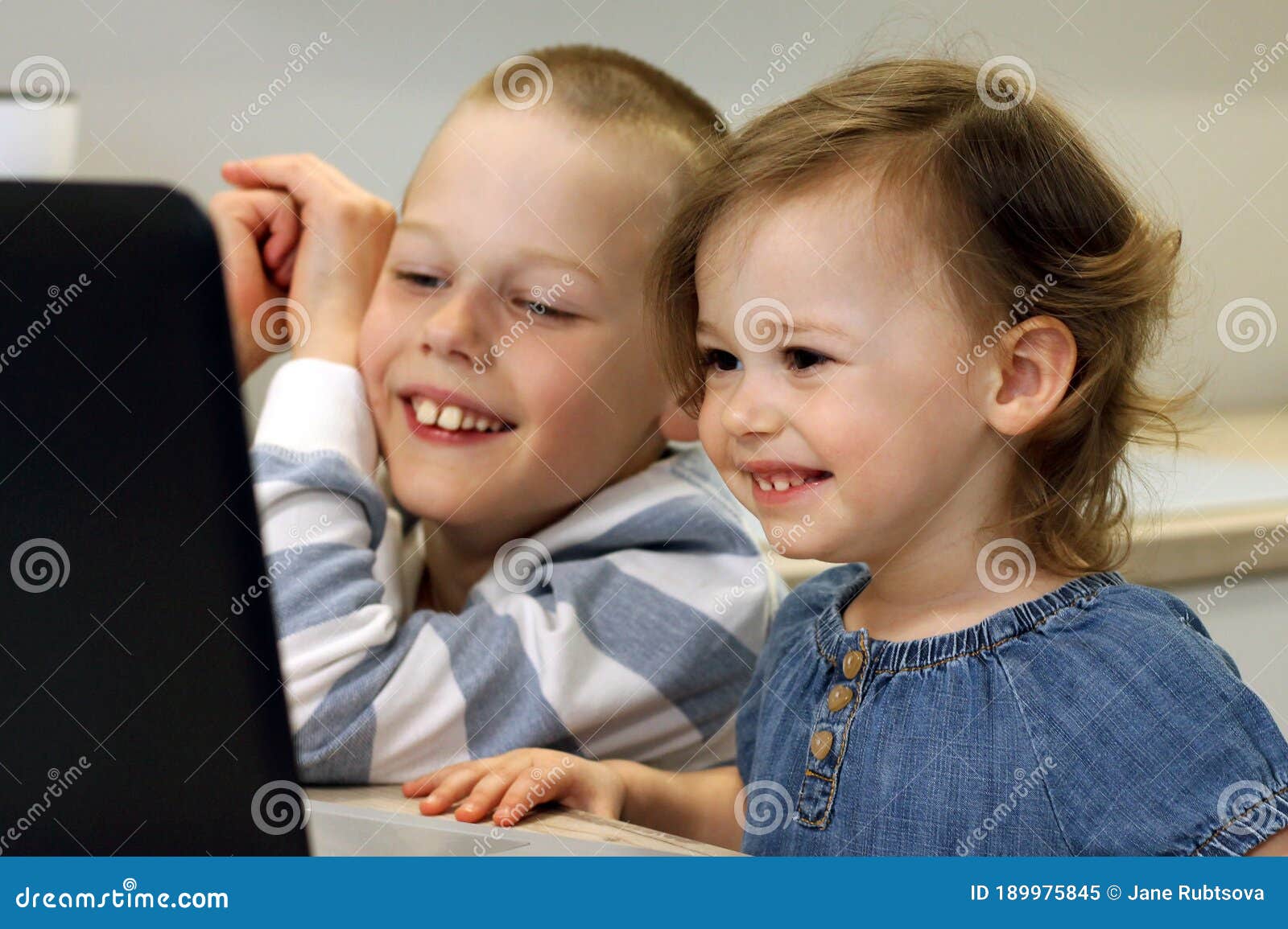 Two Laughing Children are Sitting in the Kitchen and Looking at the ...