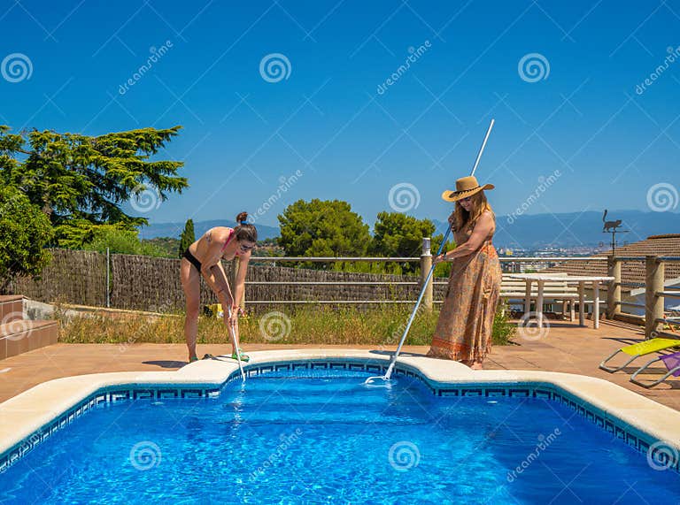 Two Lesbian Couple Friends Smiling And Cleaning A Swimming Pool