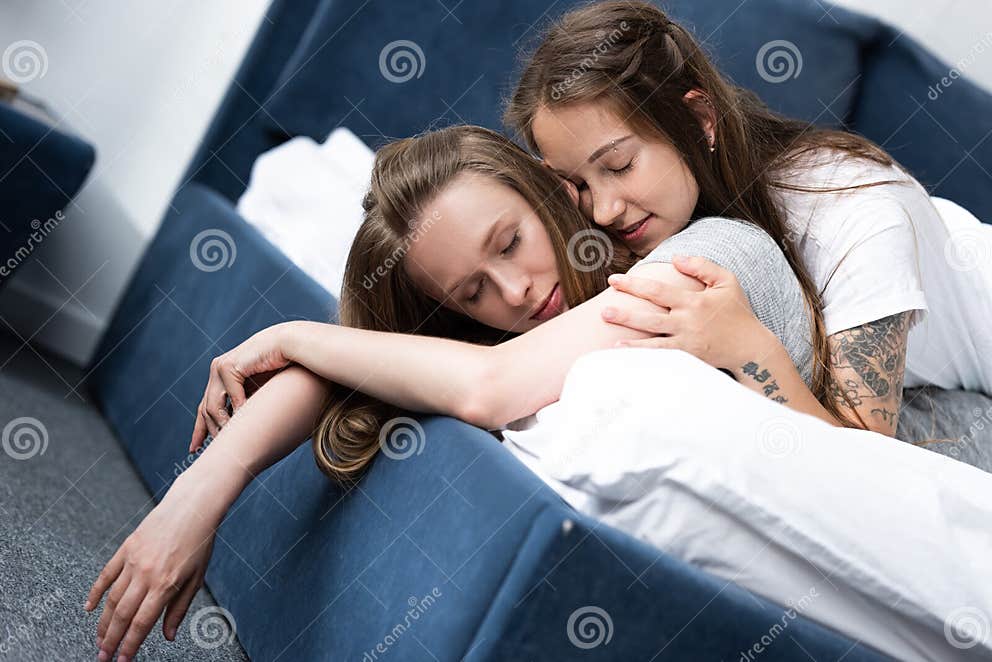 Two Lesbians Embracing With Closed Eyes While Lying On Bed In Morning