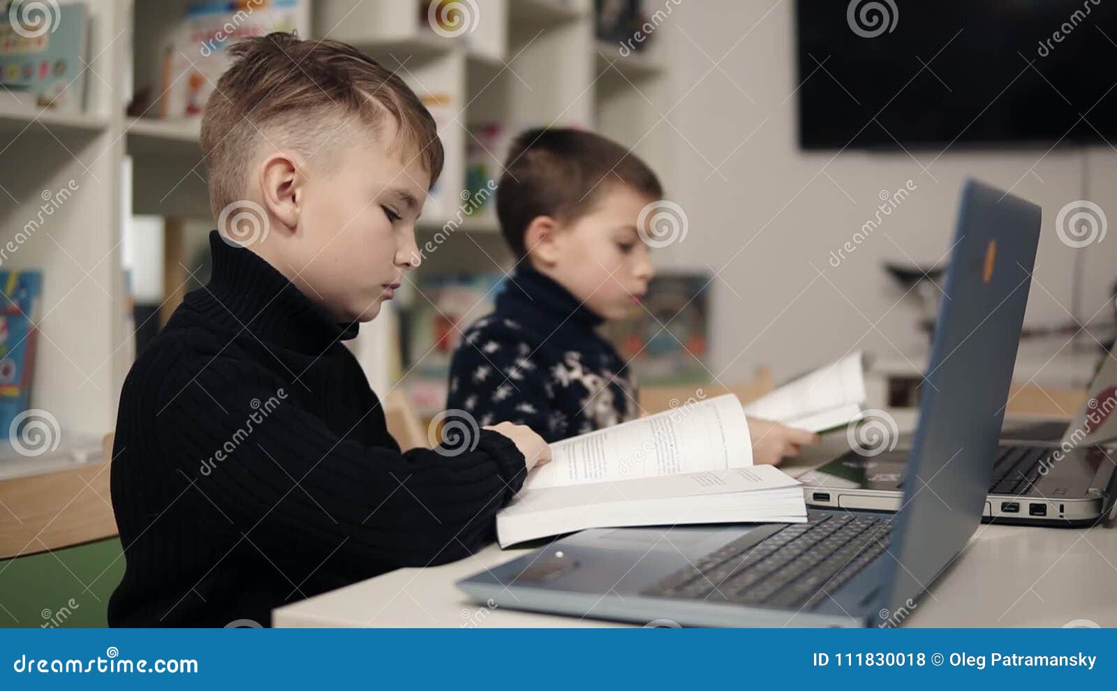 Two Little Boys Reading Books in a Classroom Sitting in Front of ...