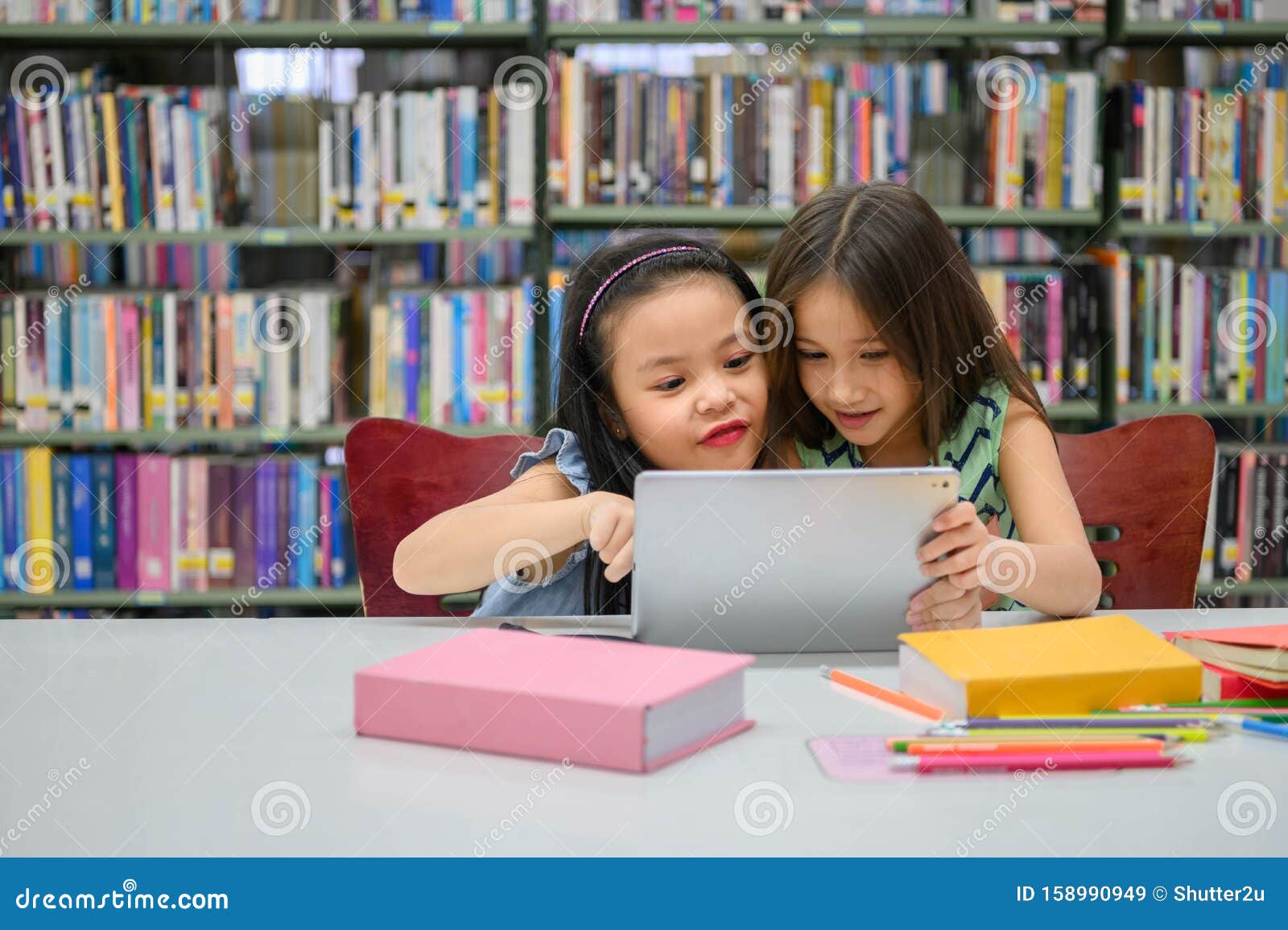 Two Little Happy Cute Girls Playing on a Tablet PC Computing Device in ...