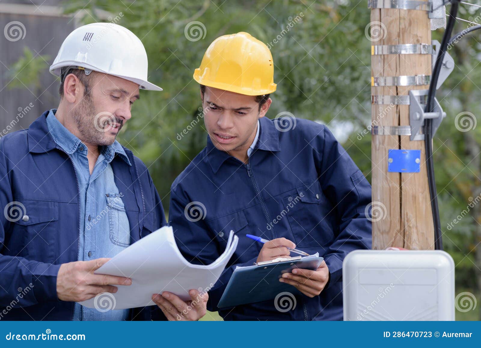 Two Male Engineers with Paperwork by Electric Pole Stock Image - Image ...