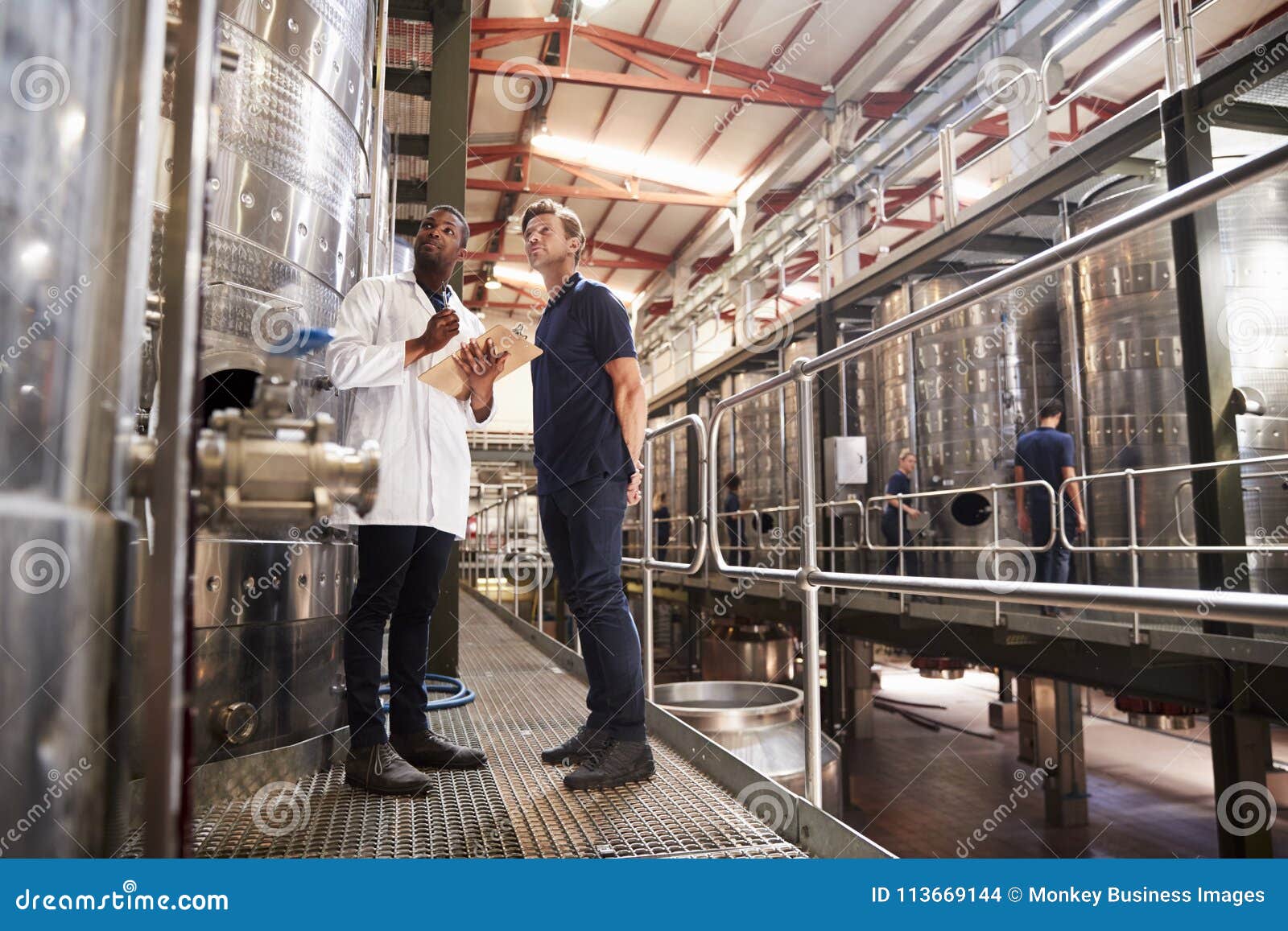 Two Male Technicians Working at a Wine Factory, Low Angle Stock Photo ... Two Male Technicians Working at a Wine Factory, Low Angle Stock Photo ...