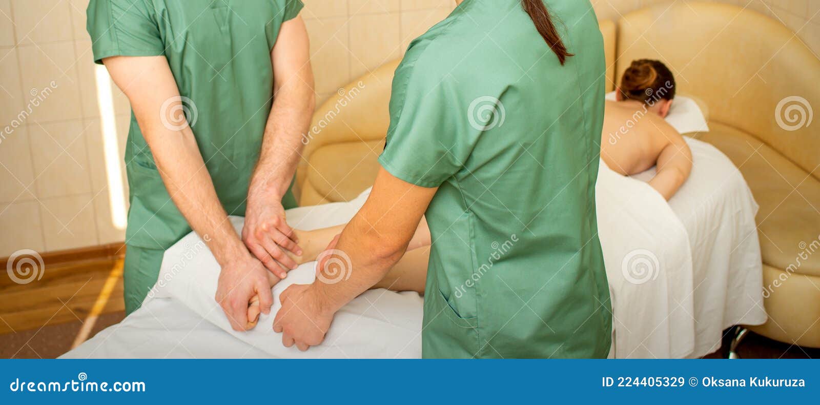 Two Masseurs Do Foot Massage In Four Hands For A Female Client In A Spa