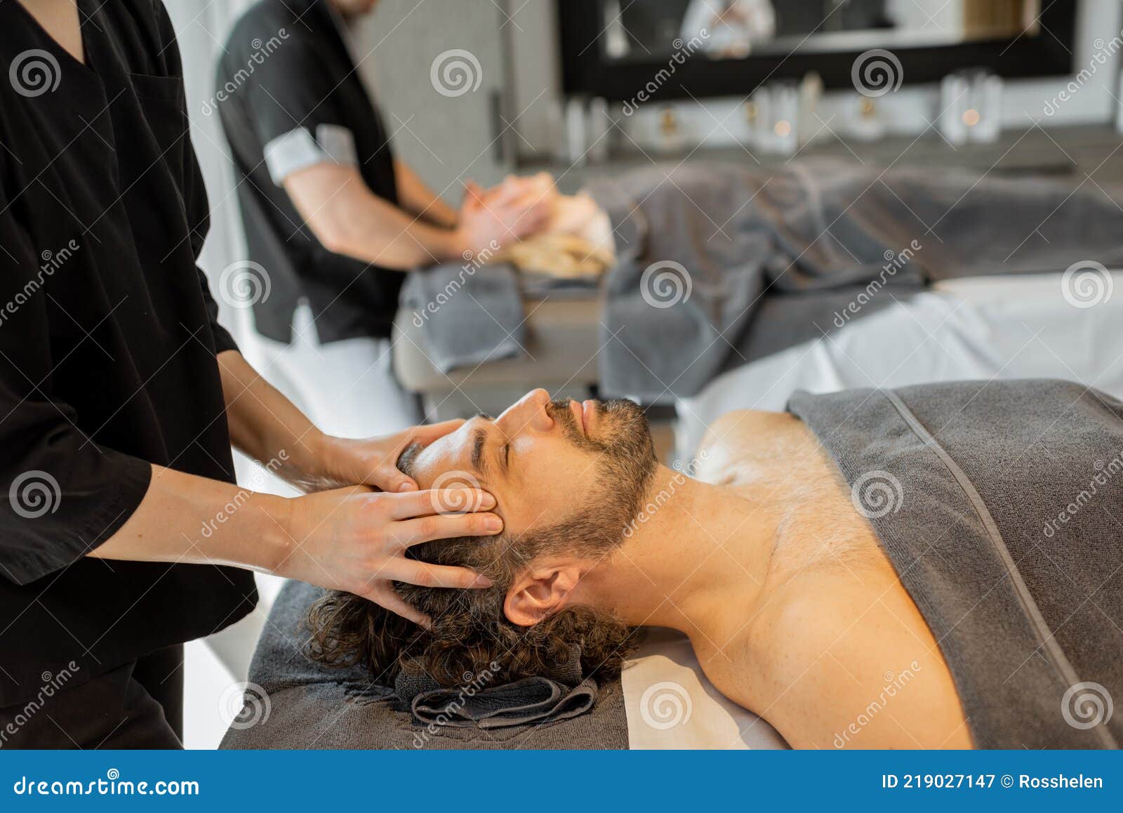 Two Masseurs Doing Facial Massage To A Couple At Spa Salon Stock Image