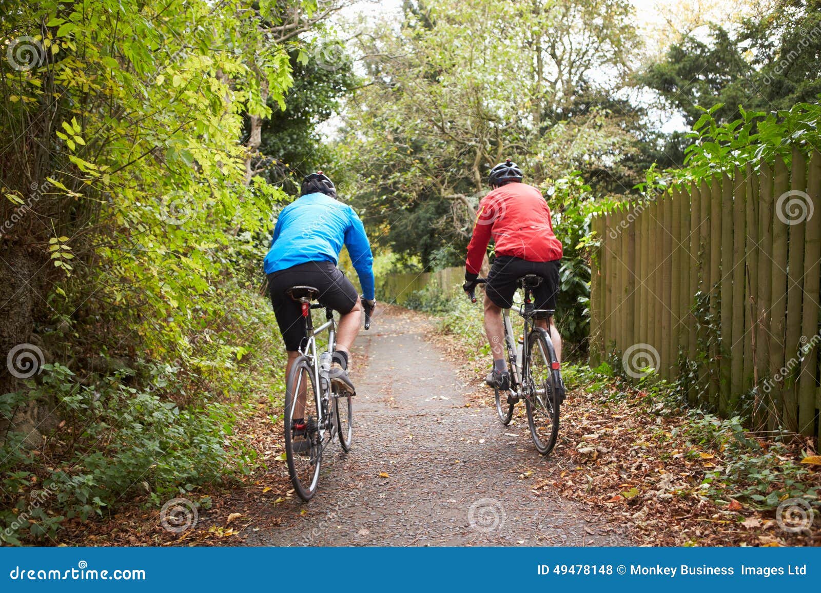 Two Mature Male Cyclists Riding Bikes Along Path Stock Photo - Image of ...