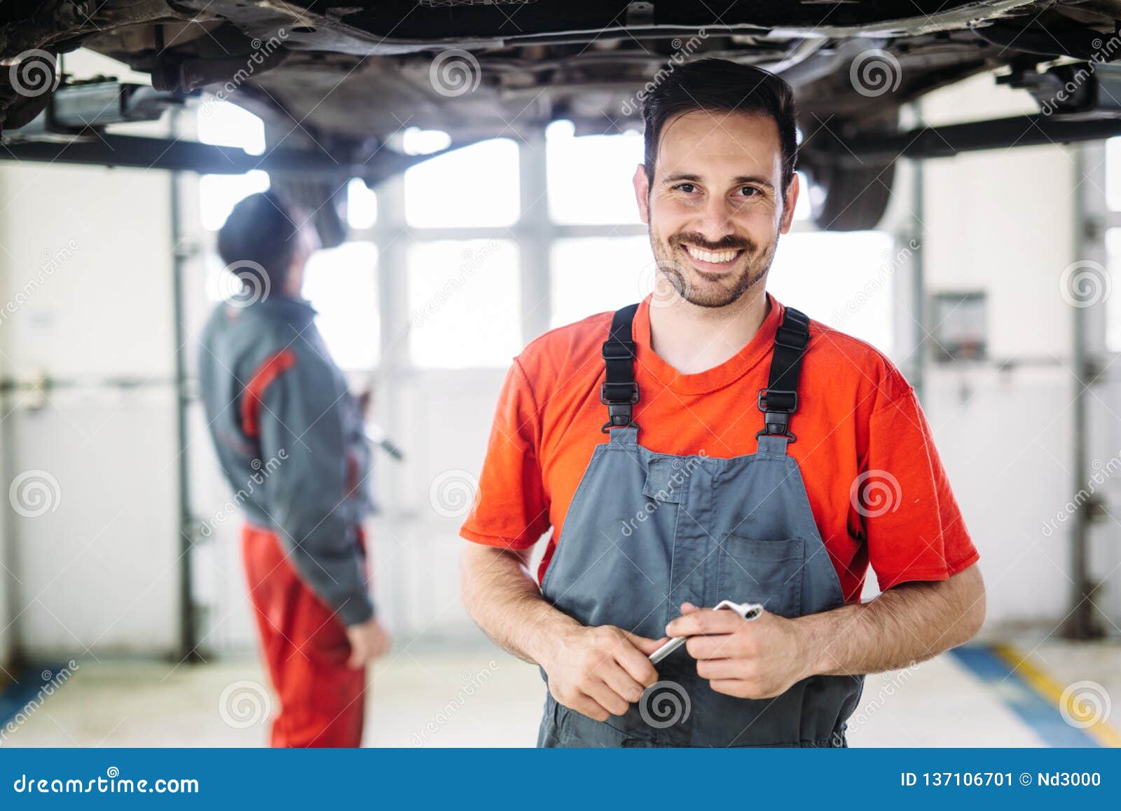 Two Mechanics in Uniform are Working in Auto Service with Lifted ...