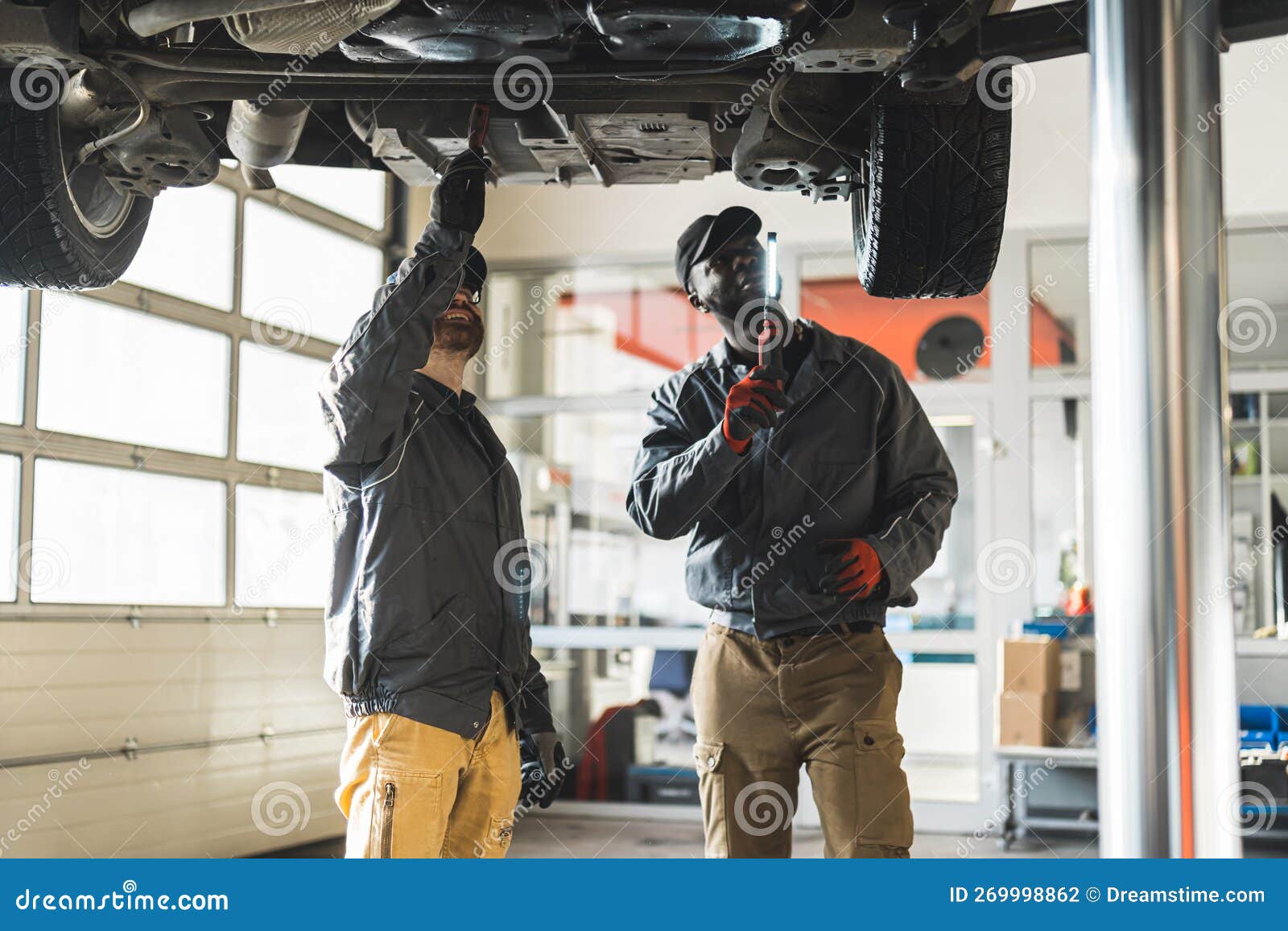 Two Mechnics during Work. One Holding a Flashlight, Another Inspecting ...