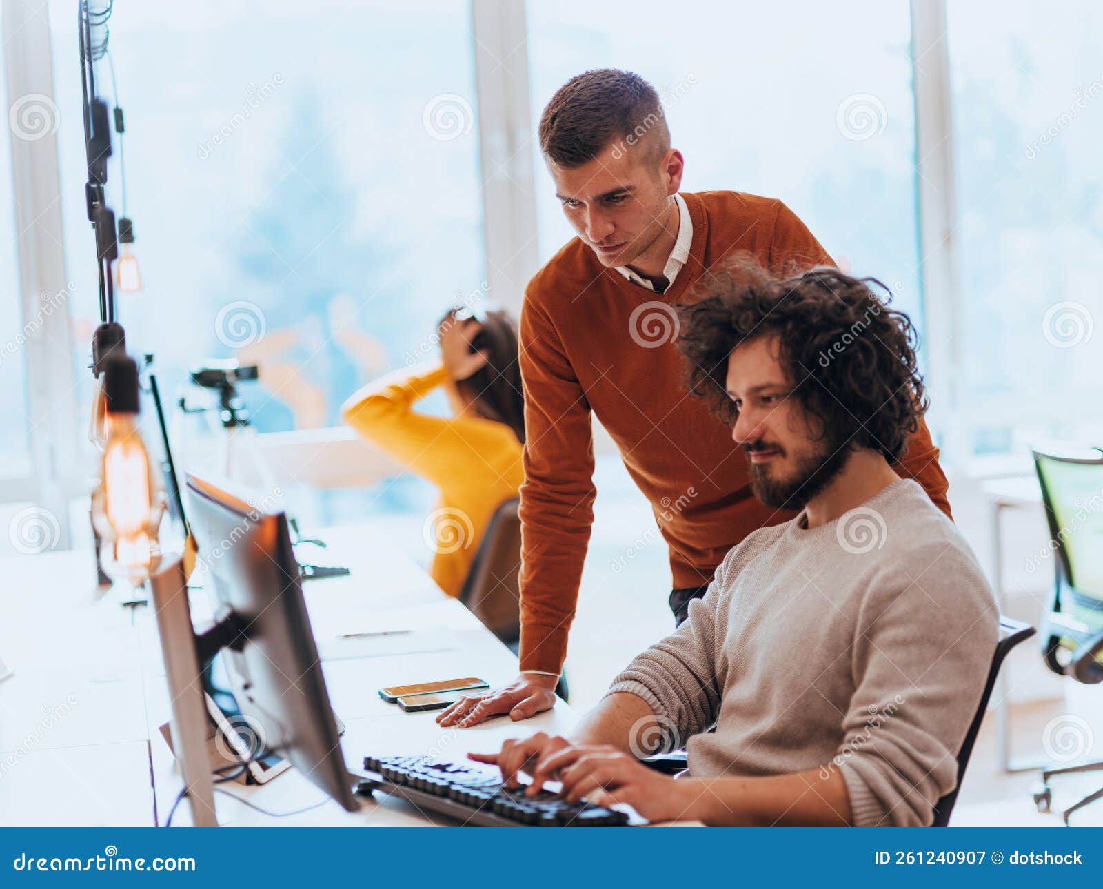Two Men Discuss a Project while Looking at a Computer Monitor in a ...