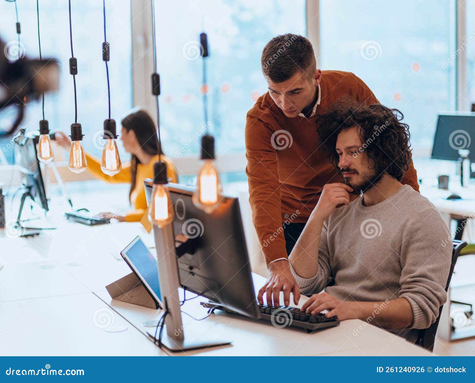 Two Men Discuss a Project while Looking at a Computer Monitor in a ...