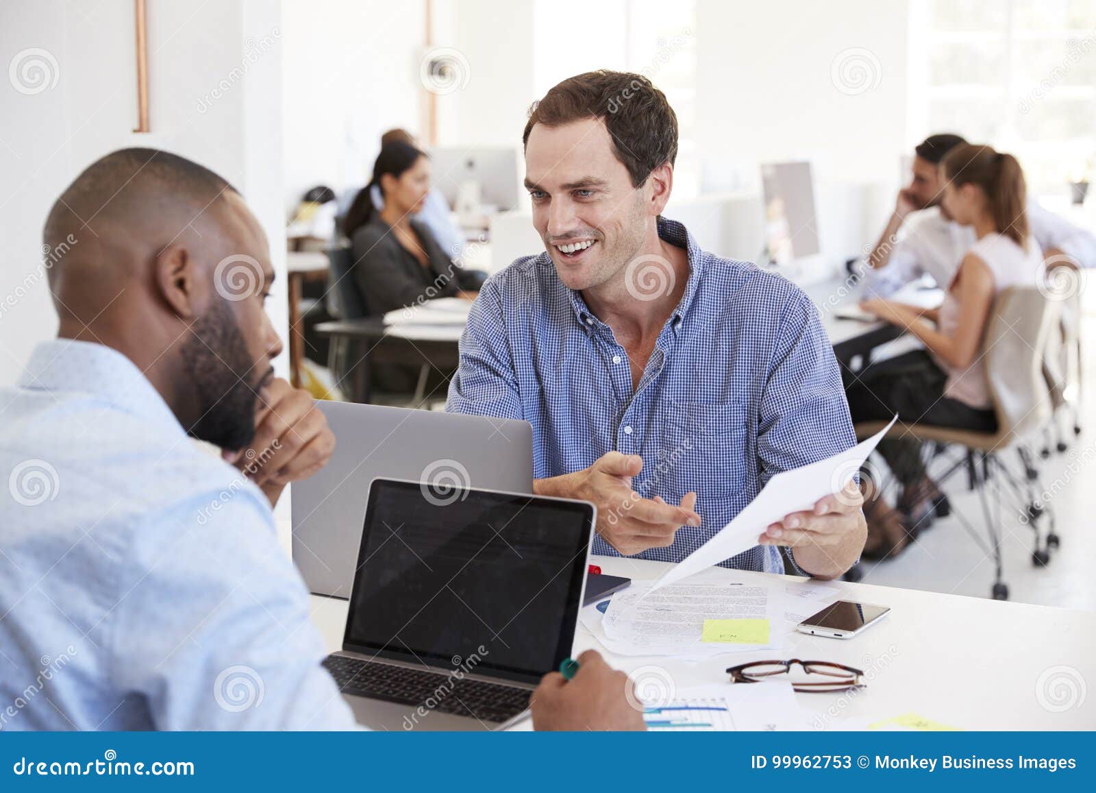 Two Men Discussing Business Documents in a Busy Office Stock Image ...