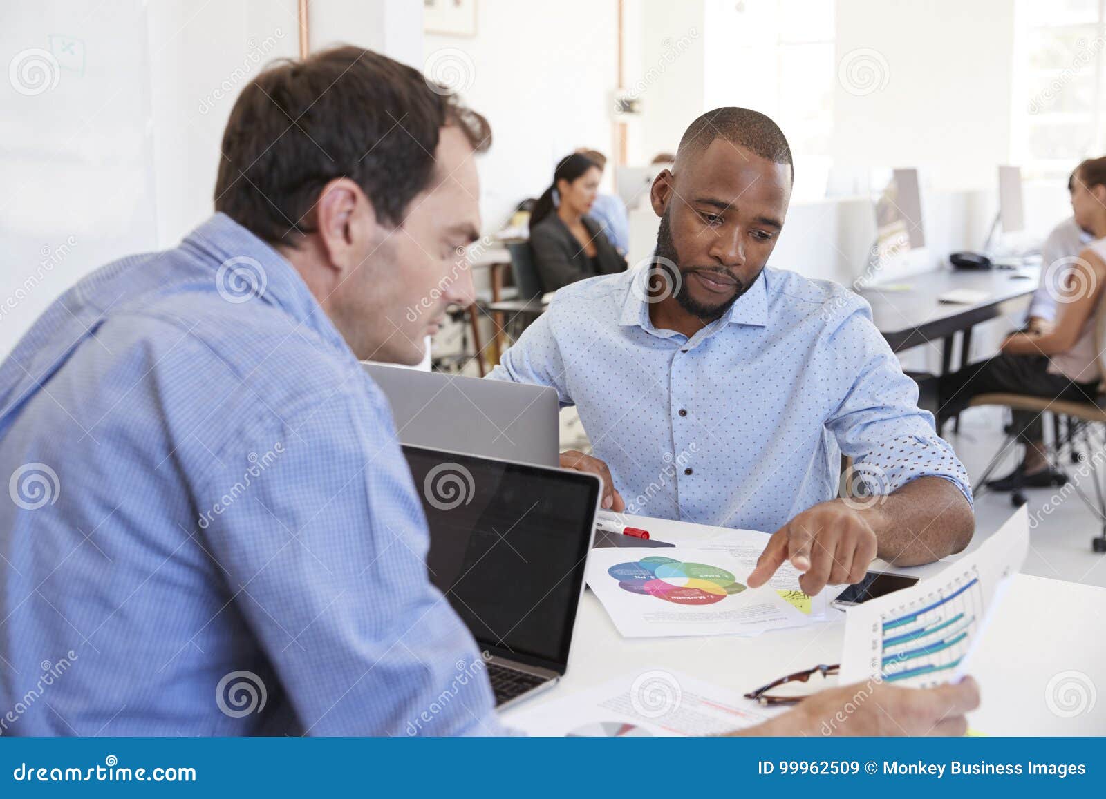 Two Men Discussing Documents in a Busy Office Stock Image - Image of ...