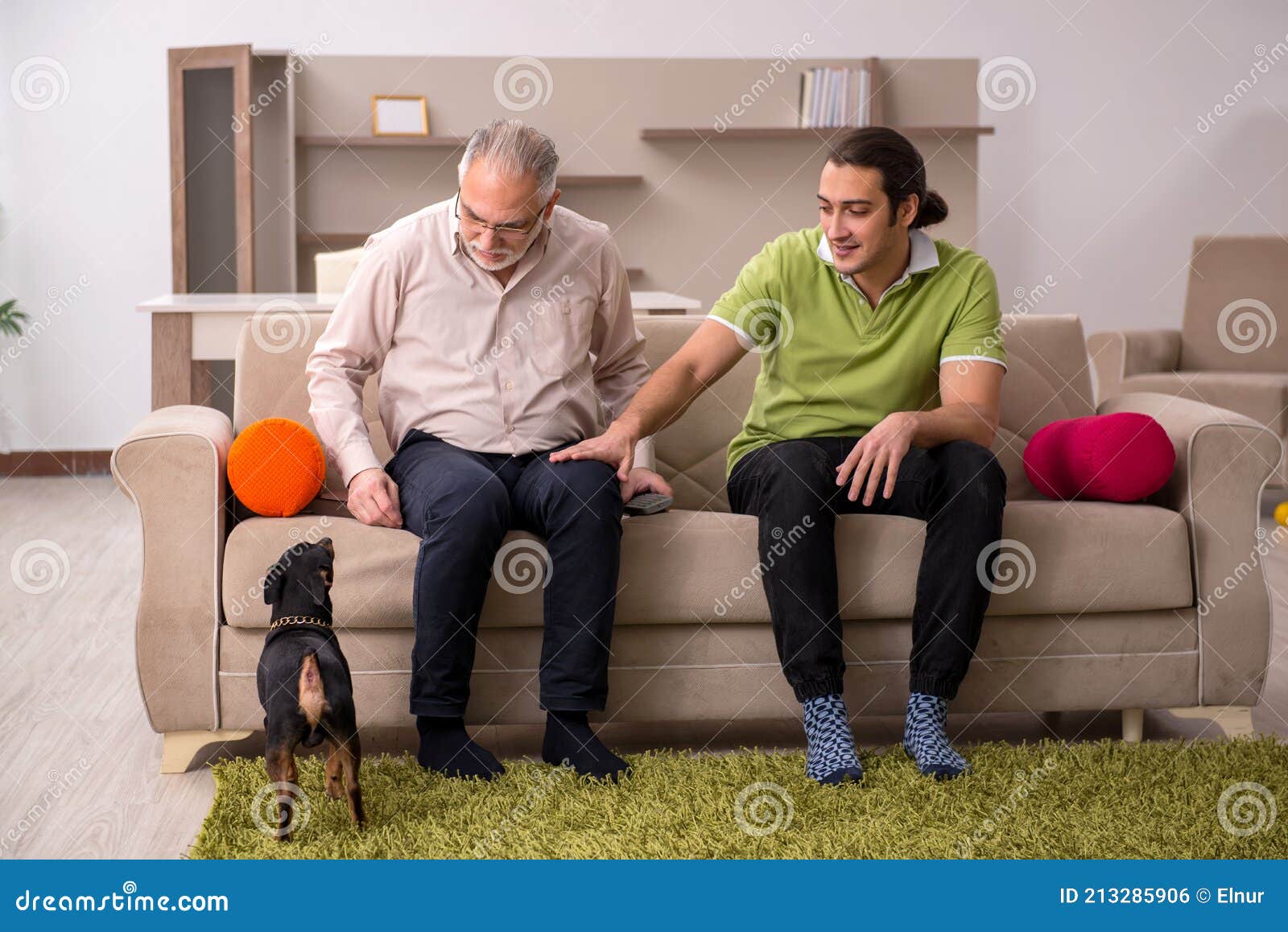 Two men with dog at home stock photo. Image of friend - 213285906