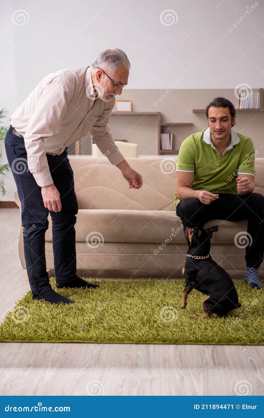Two men with dog at home stock image. Image of playing - 211894471