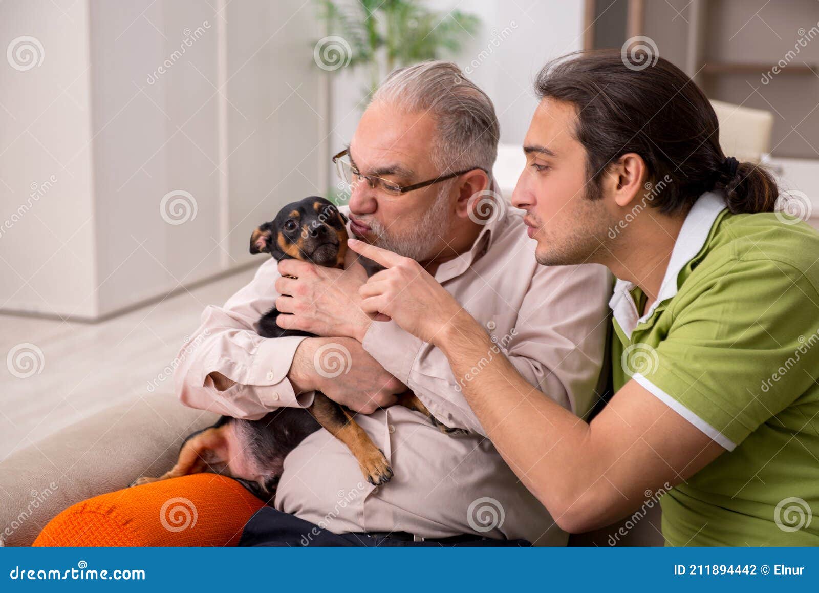 Two men with dog at home stock photo. Image of doggy - 211894442