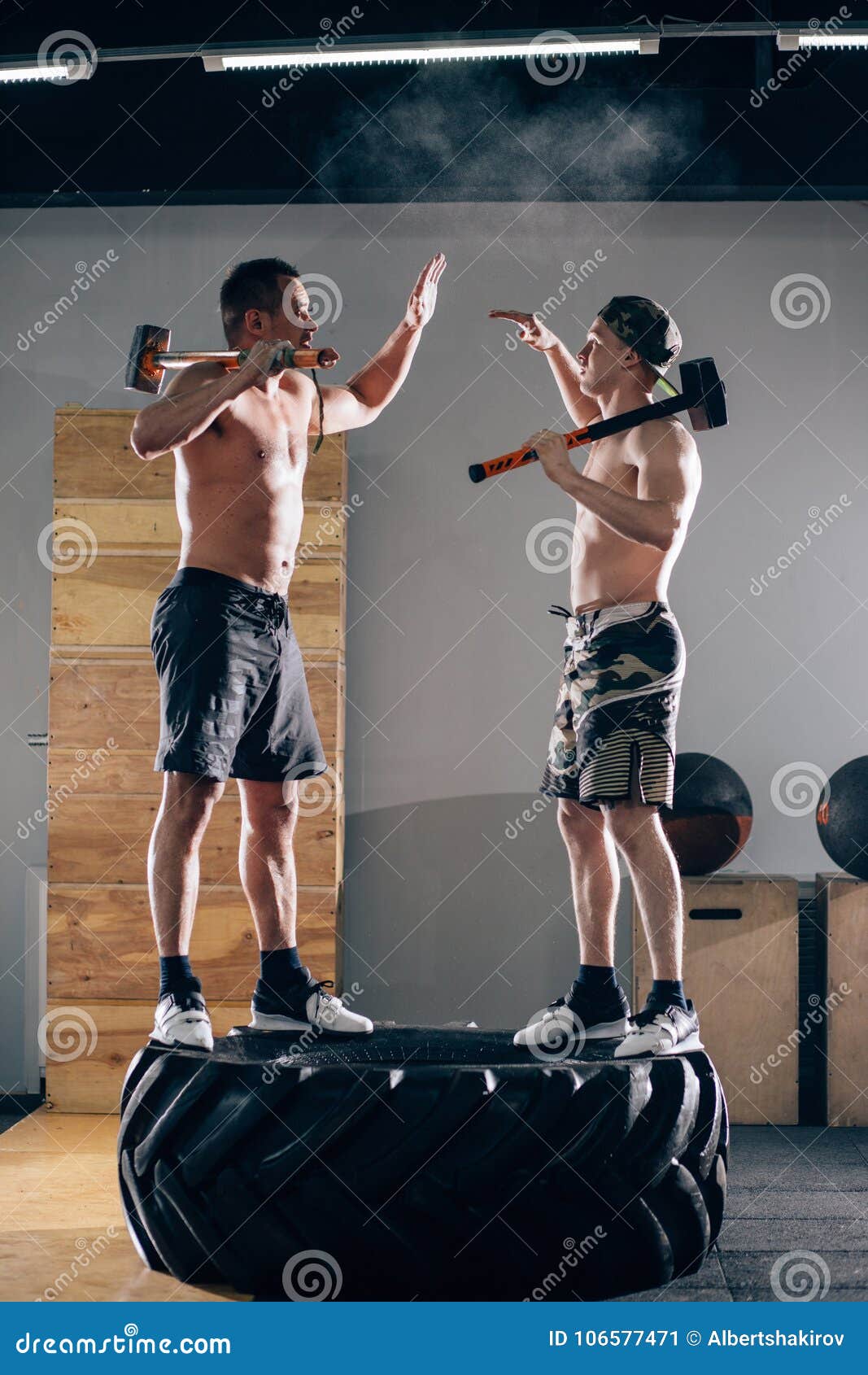 Two Men Doing High Five while Standing on Tire and Holding ...