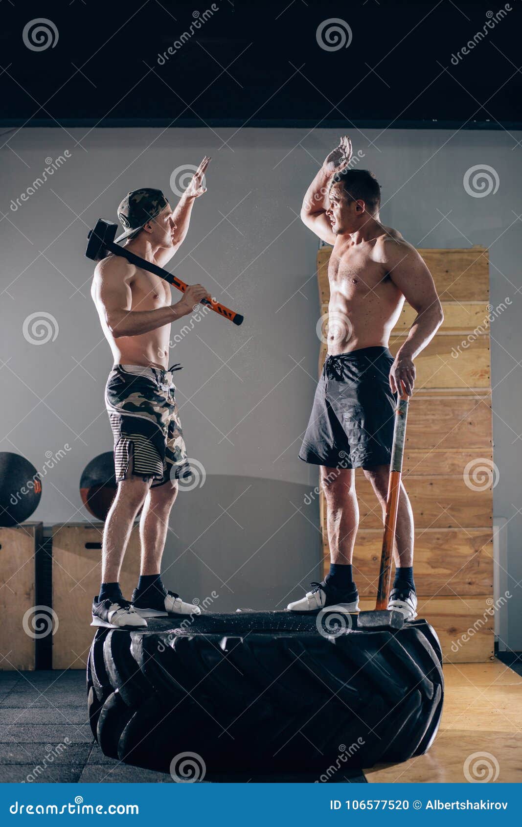 Two Men Doing High Five while Standing on Tire and Holding ...