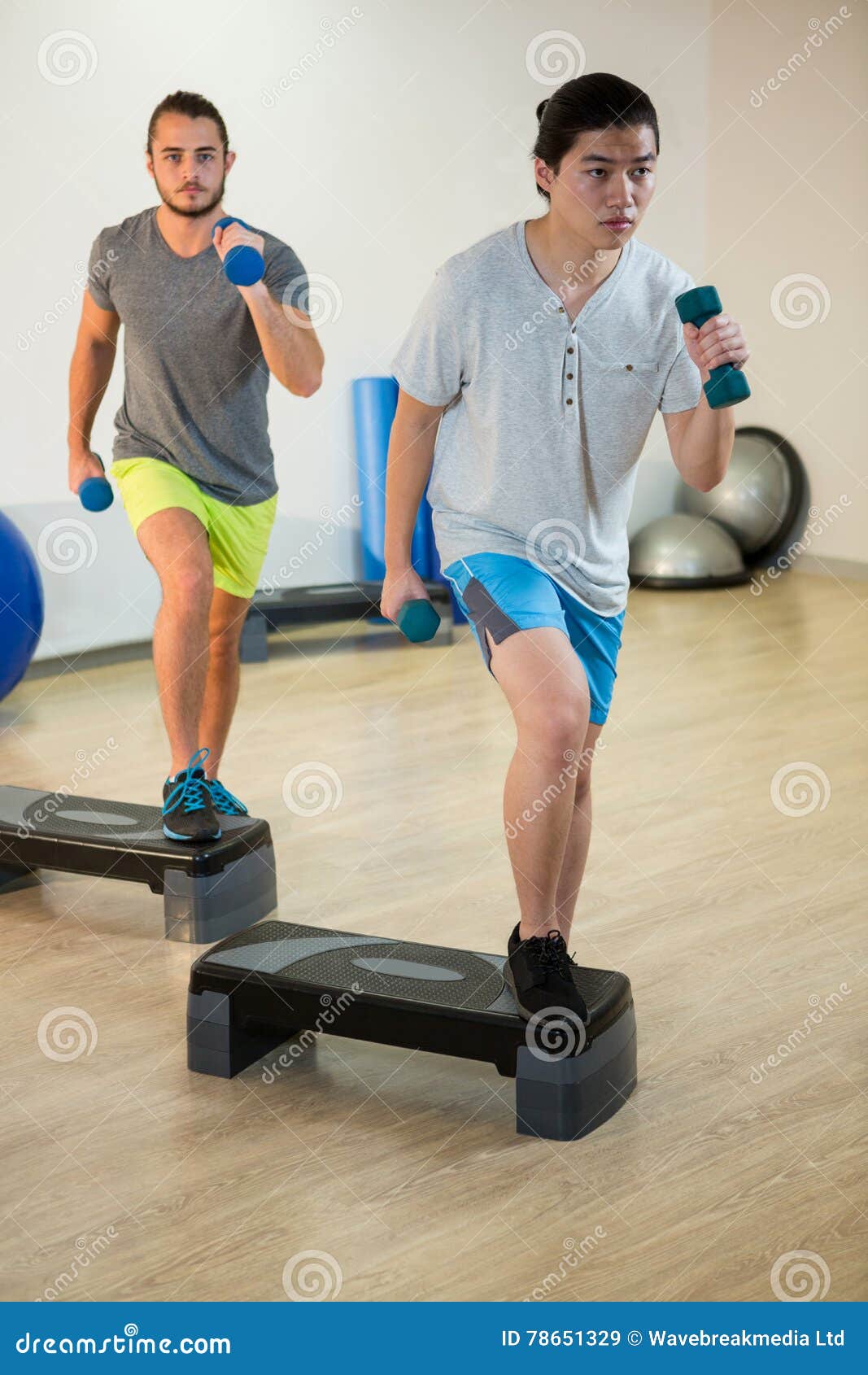 Two Men Doing Step Aerobic Exercise with Dumbbell on Stepper Stock ...