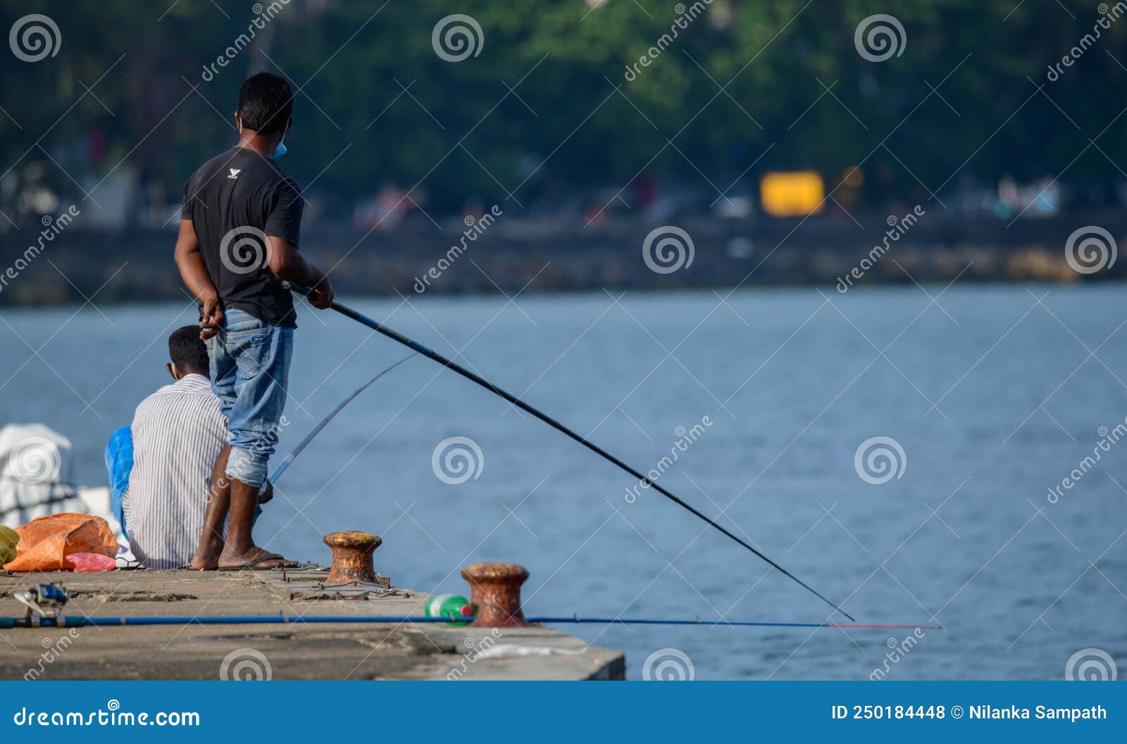 Two Men Fishing at the Peer, Using Fishing Rods Stock Photo - Image of ...