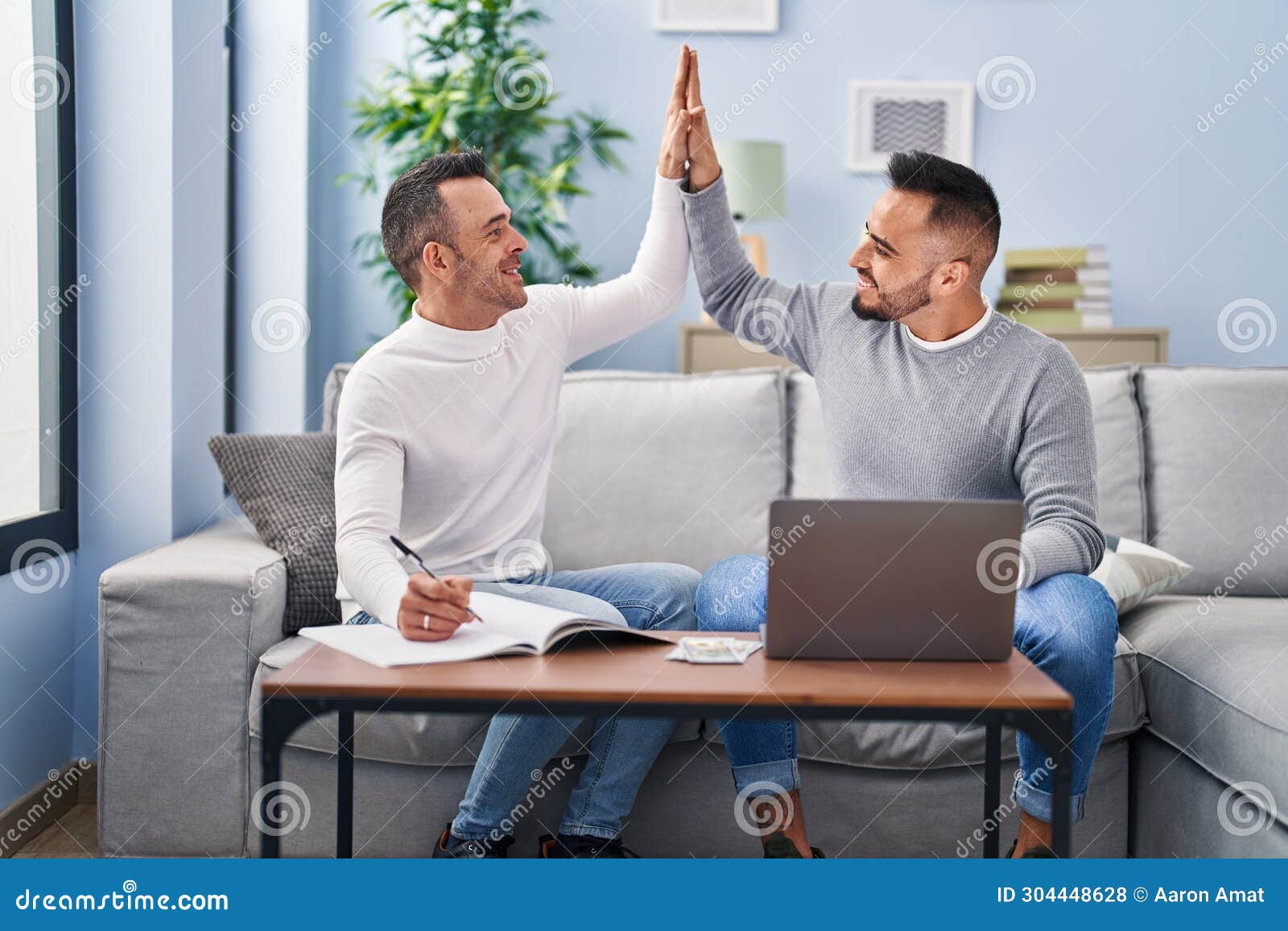 Two Men High Five with Hands Raised Up Sitting on Sofa at Home Stock ...
