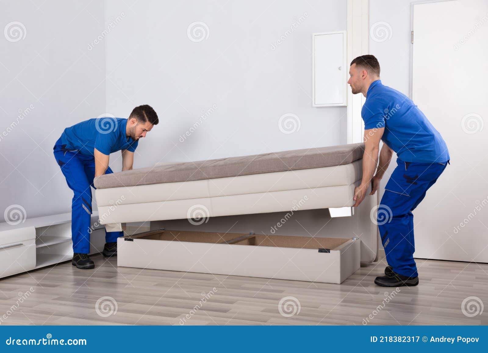 Two Men Holding Sofa in Living Room Stock Image - Image of placing ...