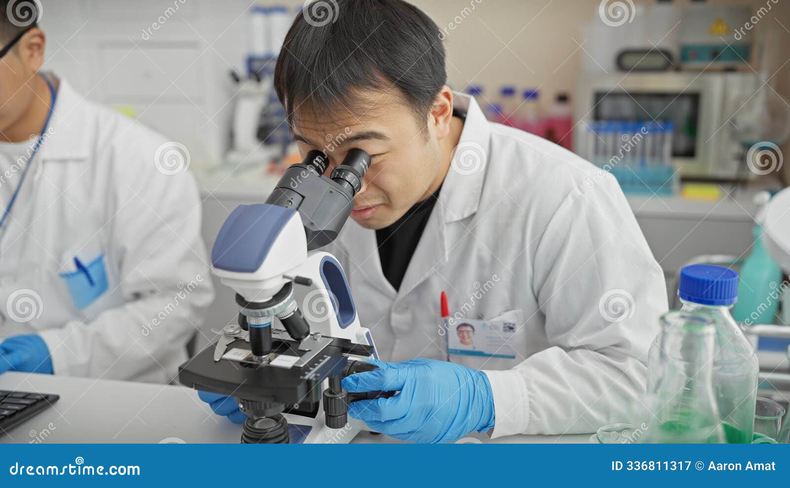 Two Men in Lab Coats Examine Samples with a Microscope in a Scientific ...