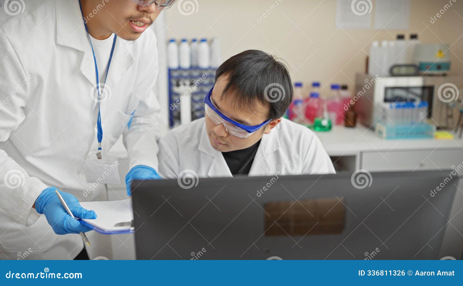 Two Men in Lab Coats Using Computer in a Science Laboratory Environment ...