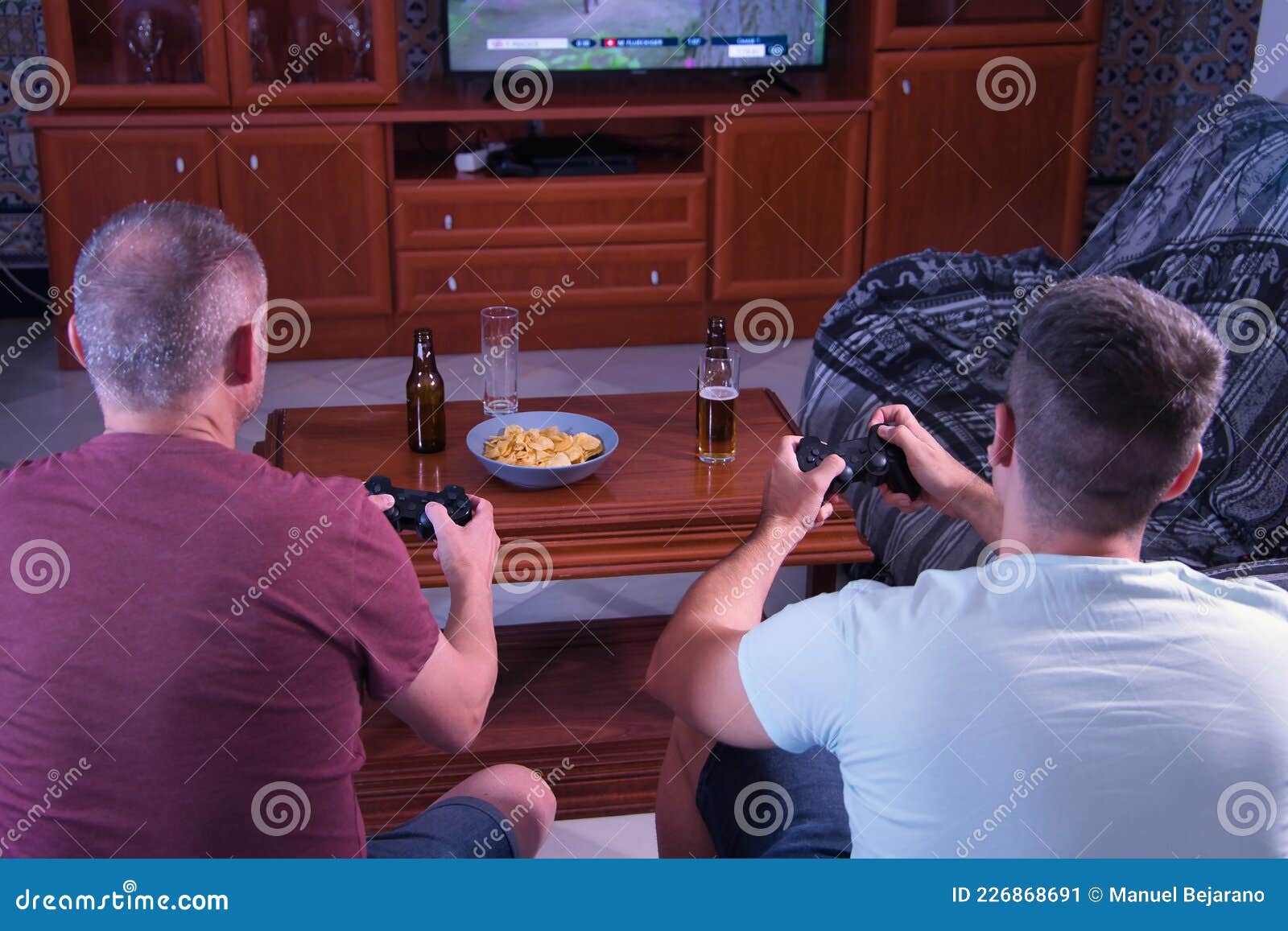 Two Men One Mature and One Young Playing Video Console Sitting on the ...