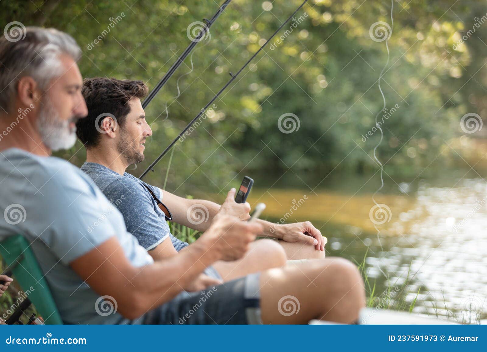 Two Men Peacefully Fishing from Riverbank Stock Image - Image of ...