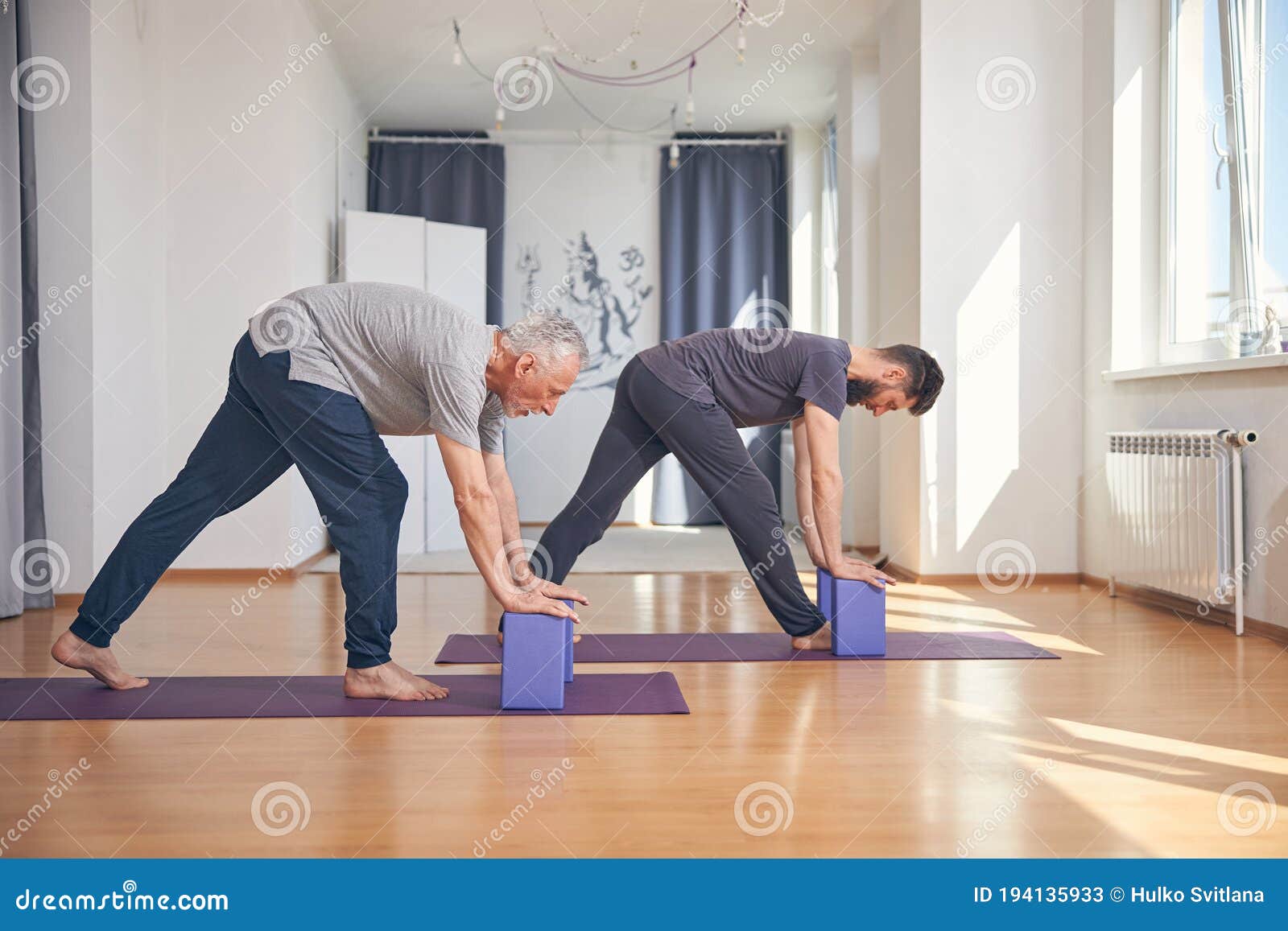 Two Men Performing a Standing Forward Bend Stock Image - Image of ...