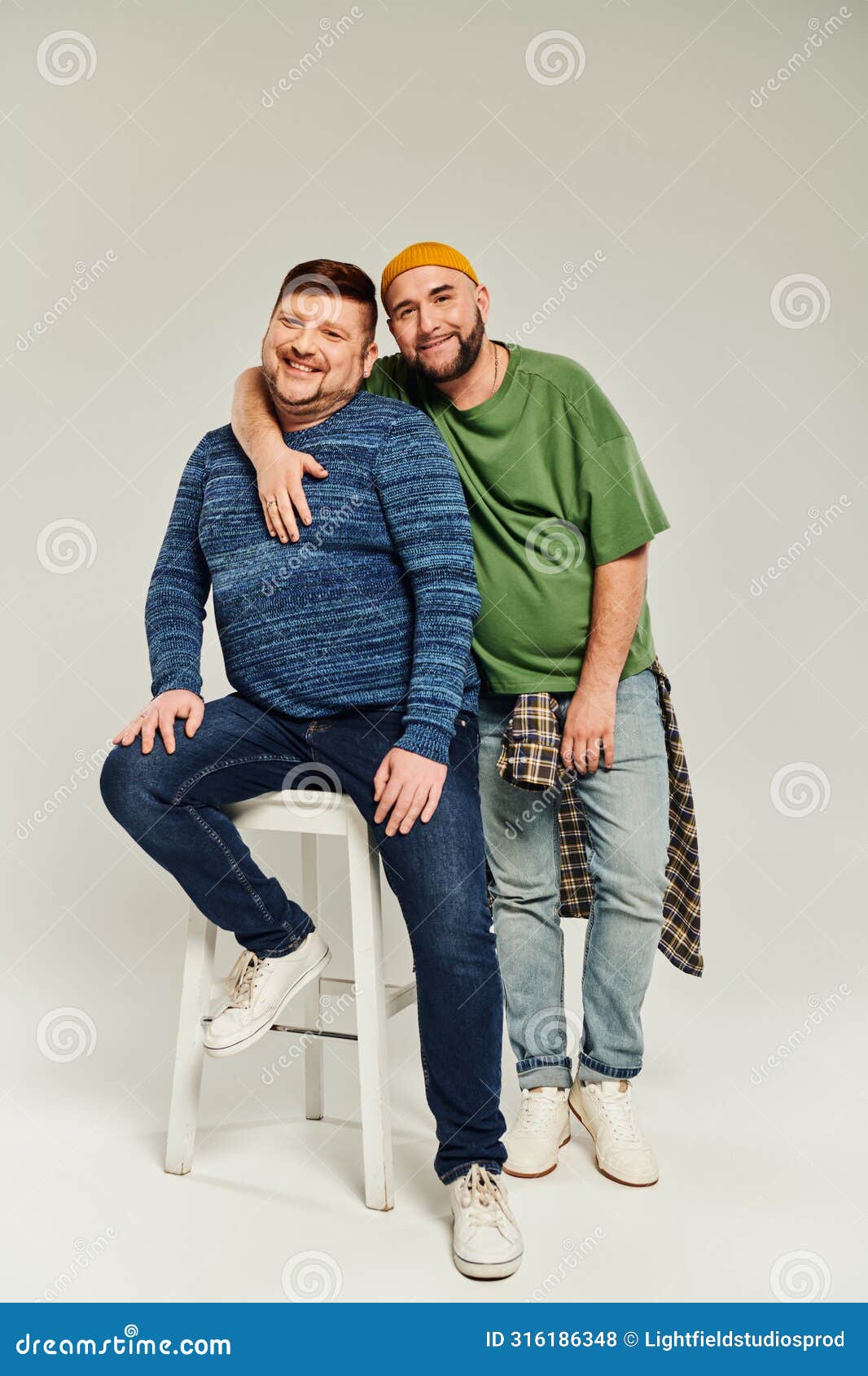 Two men posing on a stool stock photo. Image of friendship - 316186348