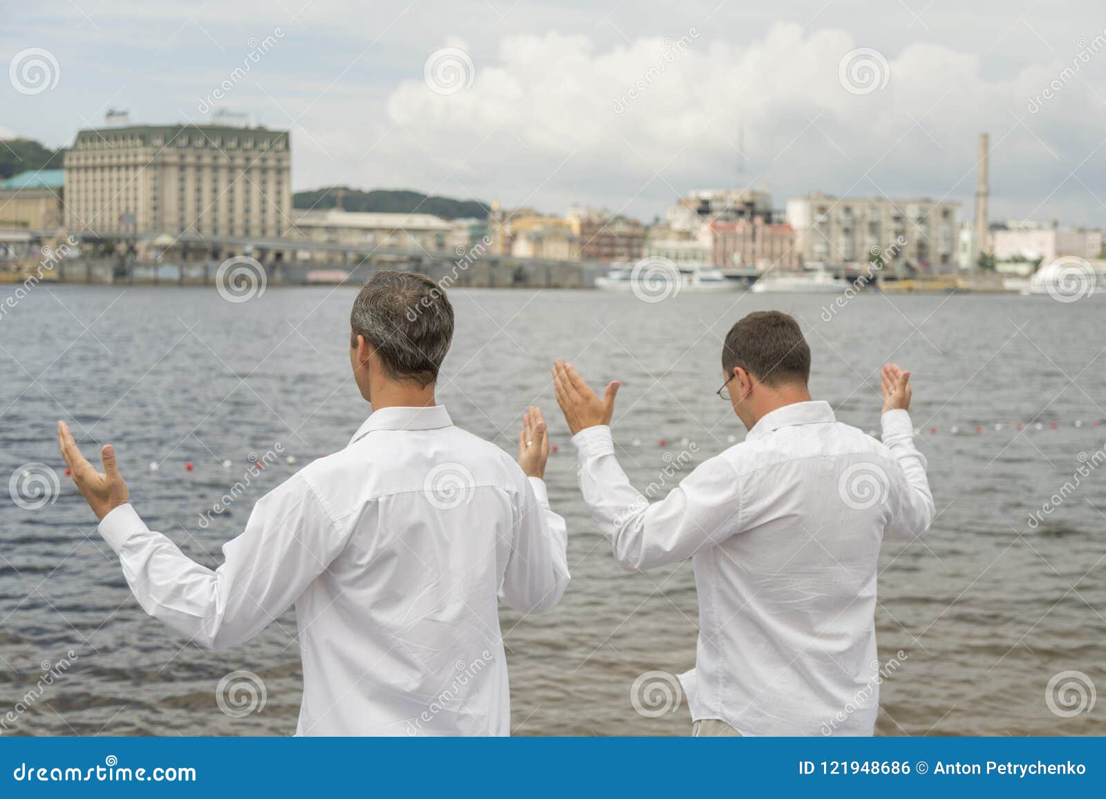 Two Men Praying. Two Men in White Clothes Pray on the River Bank ...