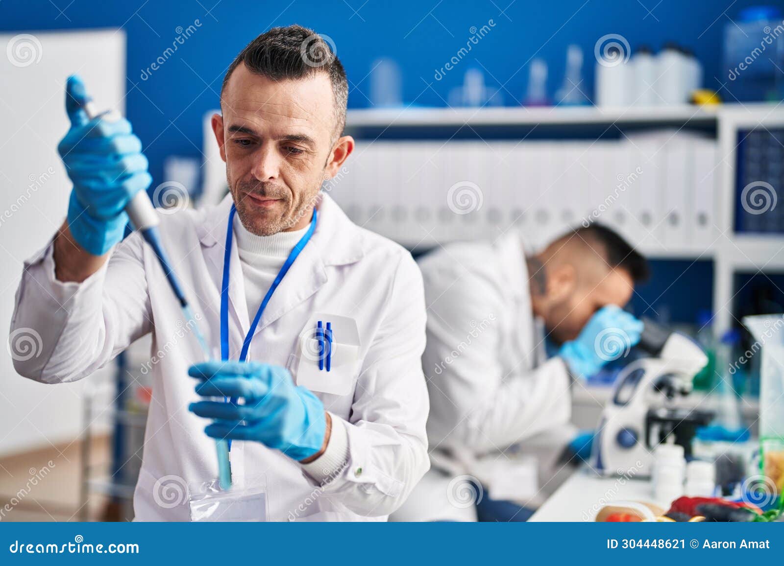 Two Men Scientists Pouring Liquid on Test Tube Using Microscope at ...
