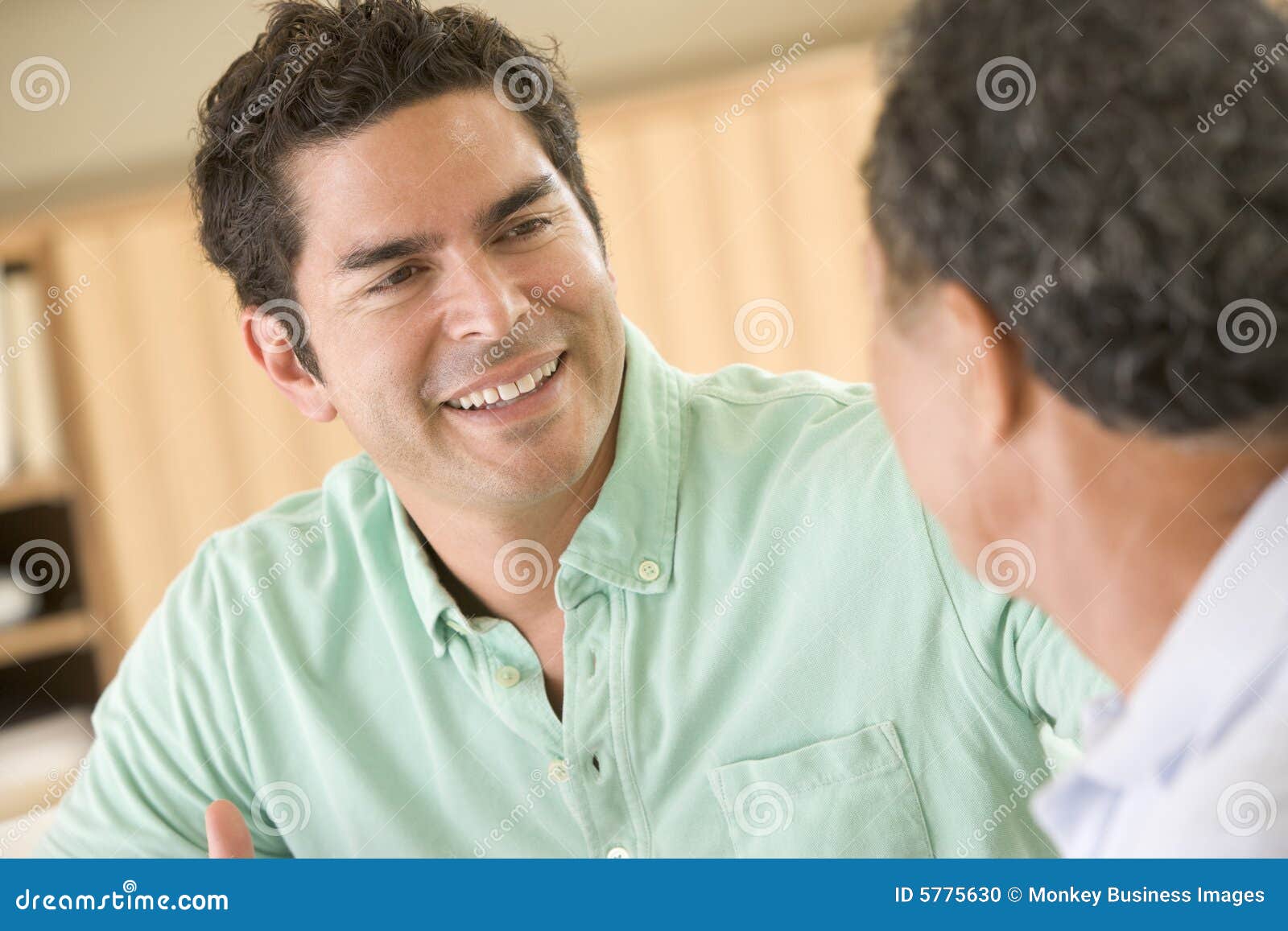Two Men Sitting in Living Room Talking and Smiling Stock Photo - Image ...