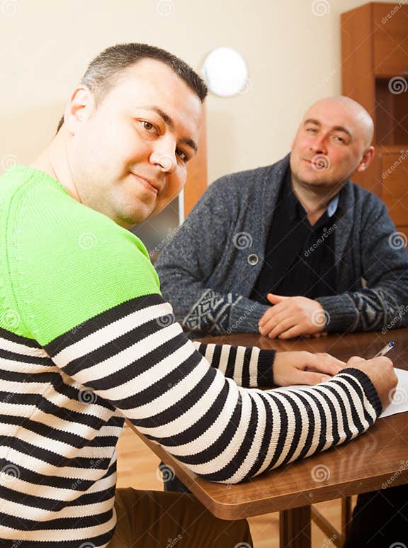 Two men sitting at table stock photo. Image of working - 43762848