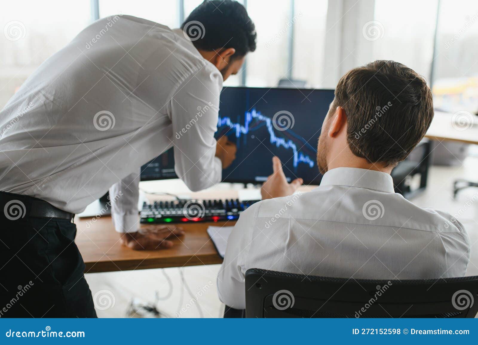 Two Men Traders Sitting at Desk at Office Together Looking at Data ...