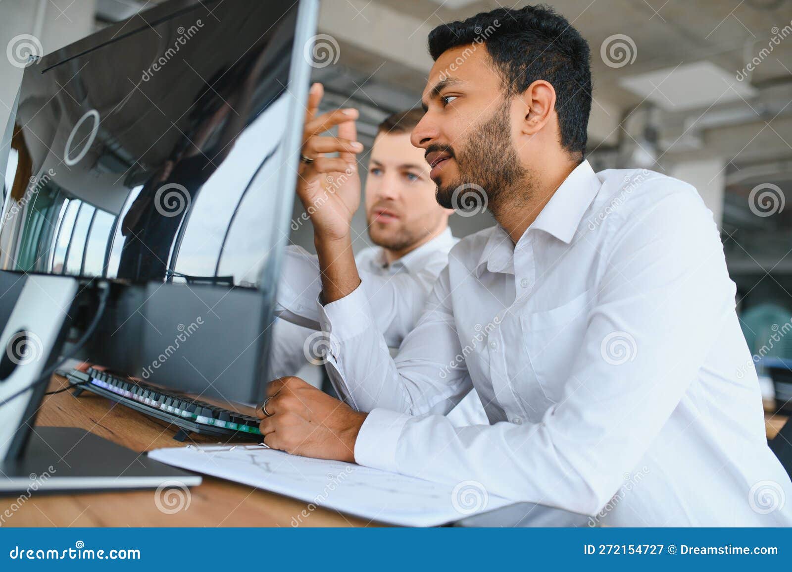Two Men Traders Sitting at Desk at Office Together Looking at Data ...