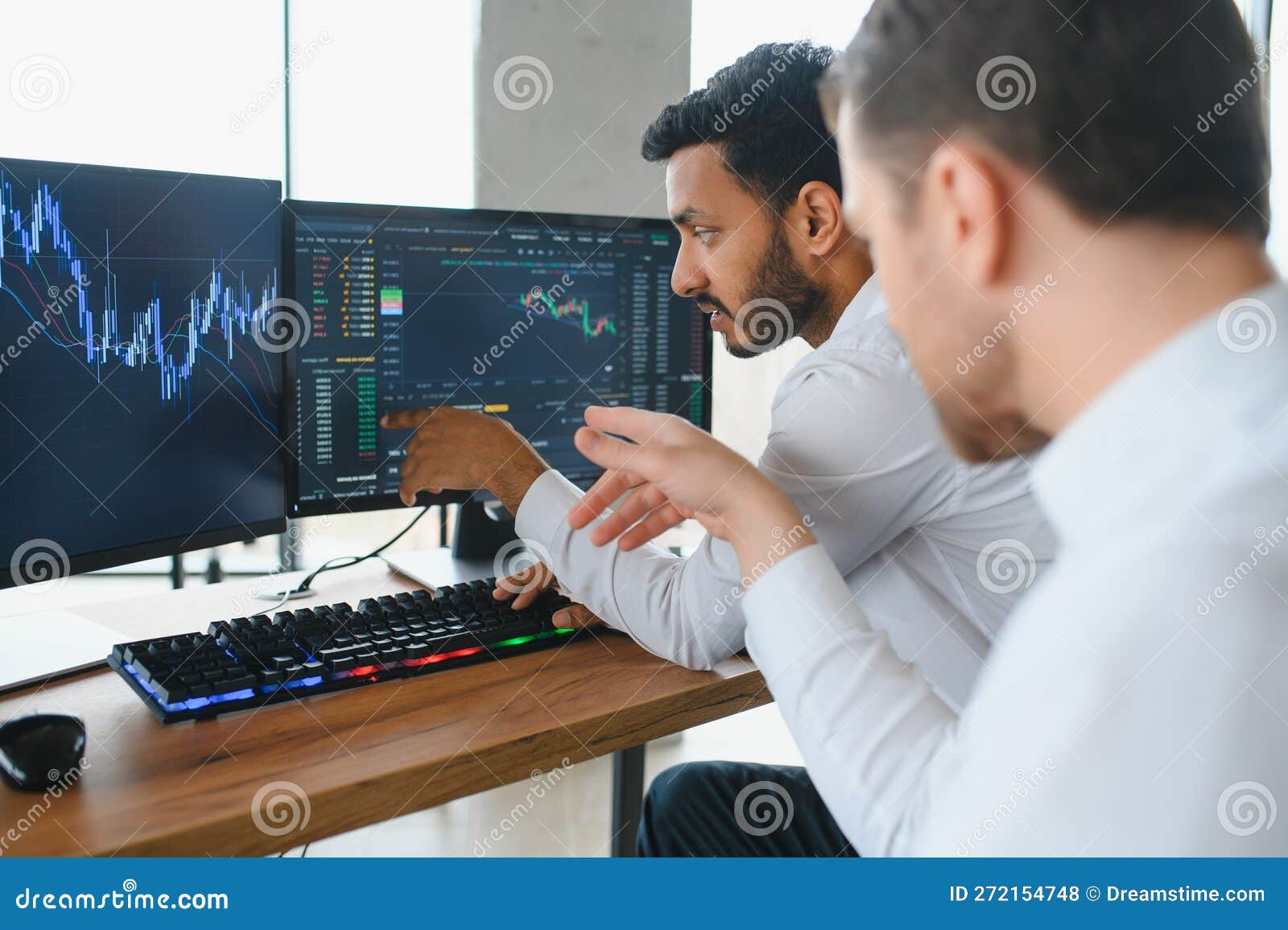 Two Men Traders Sitting at Desk at Office Together Looking at Data ...